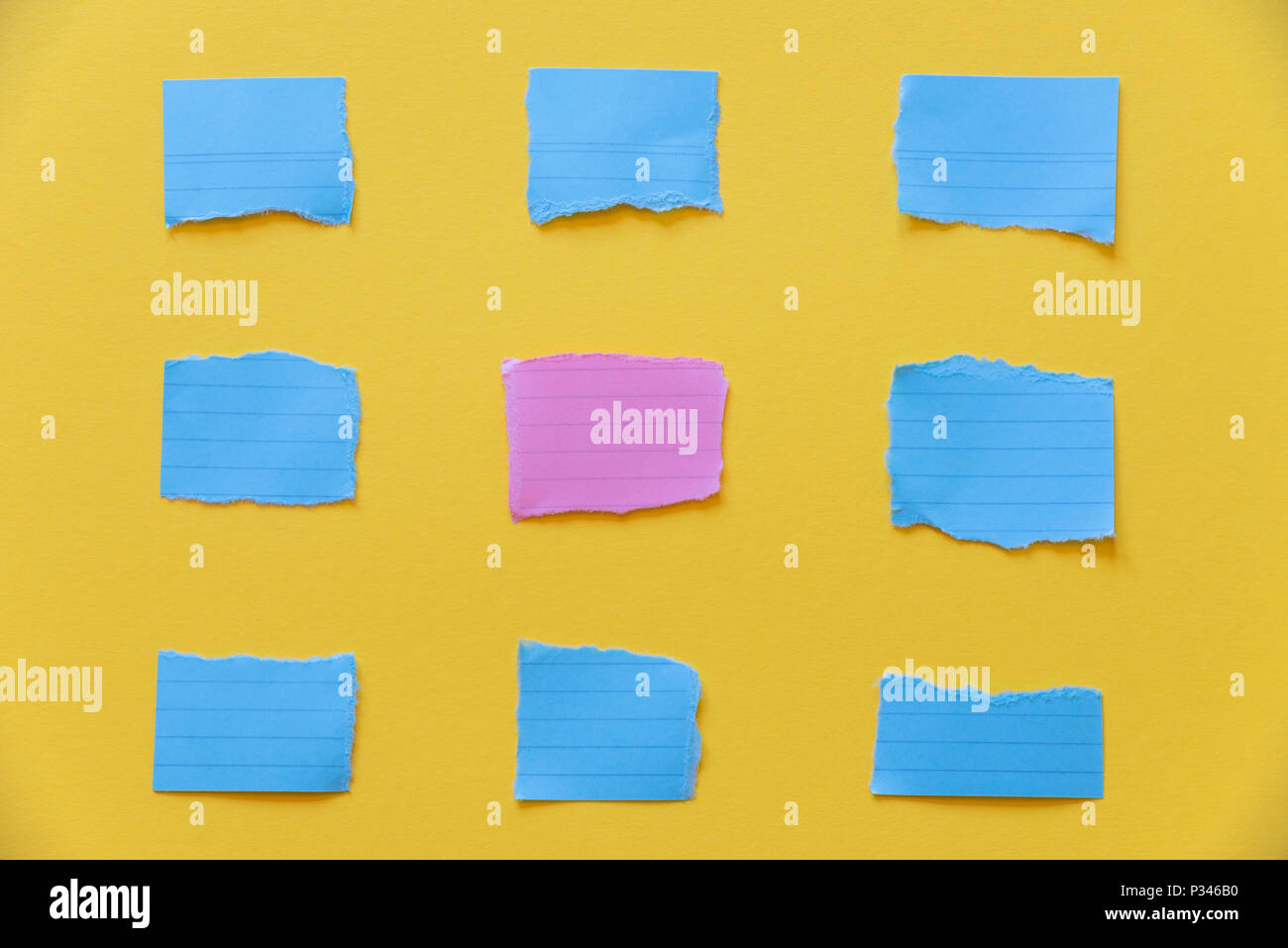 Blue and pink paper notes ripped in pieces, placed on a yellow desk ...