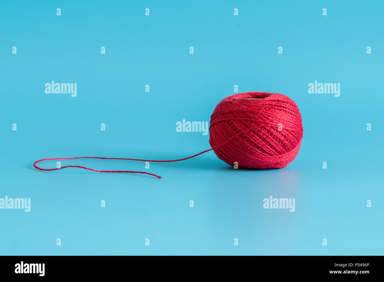 Red tangle of thread on a blue background Stock Photo - Alamy
