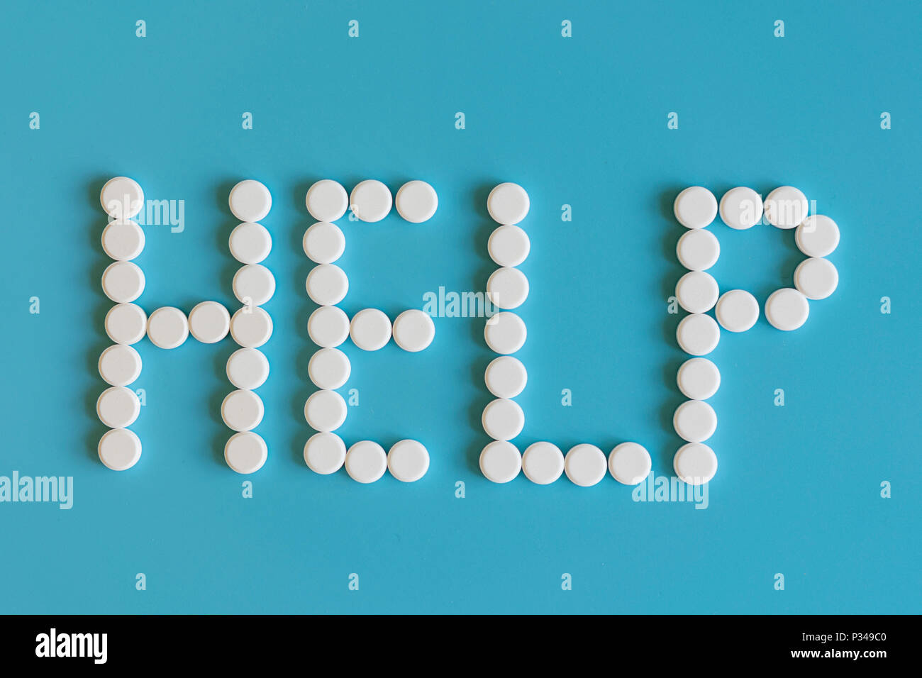 White pills on blue background word help. White medical pills on a blue ...