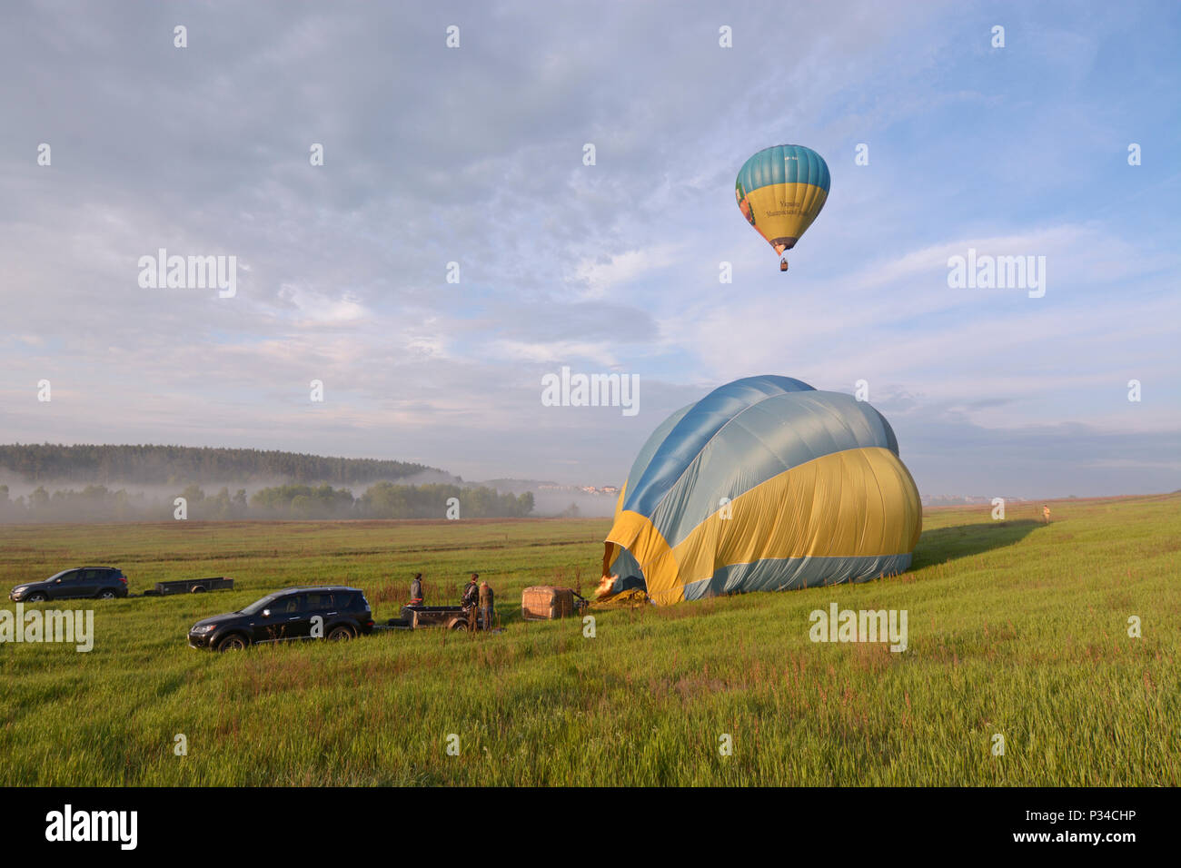 Hot-air balloon getting ready for launching, trailer with equipment is ...