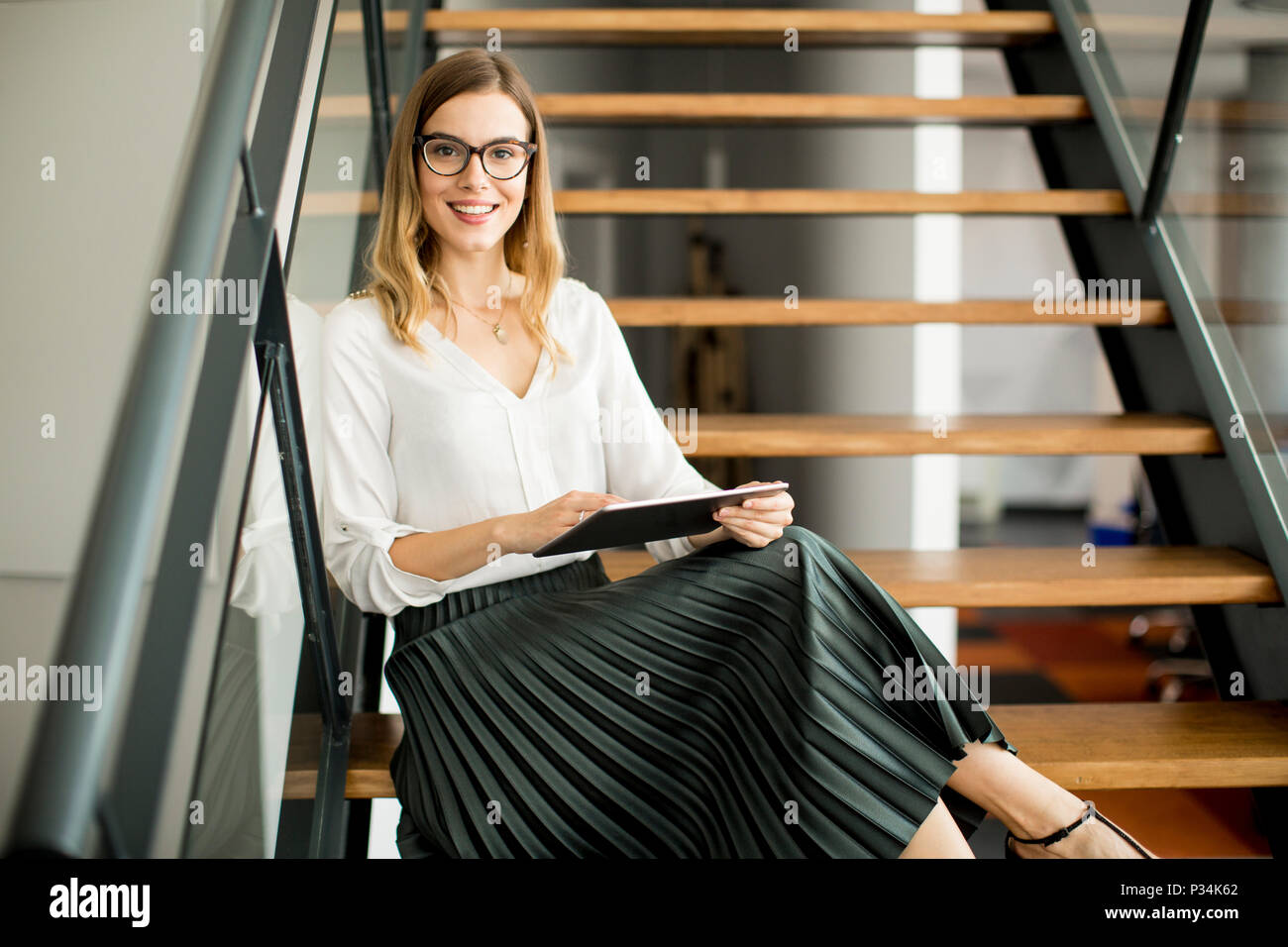 Young attractive female manager working on digital tablet while sitting ...