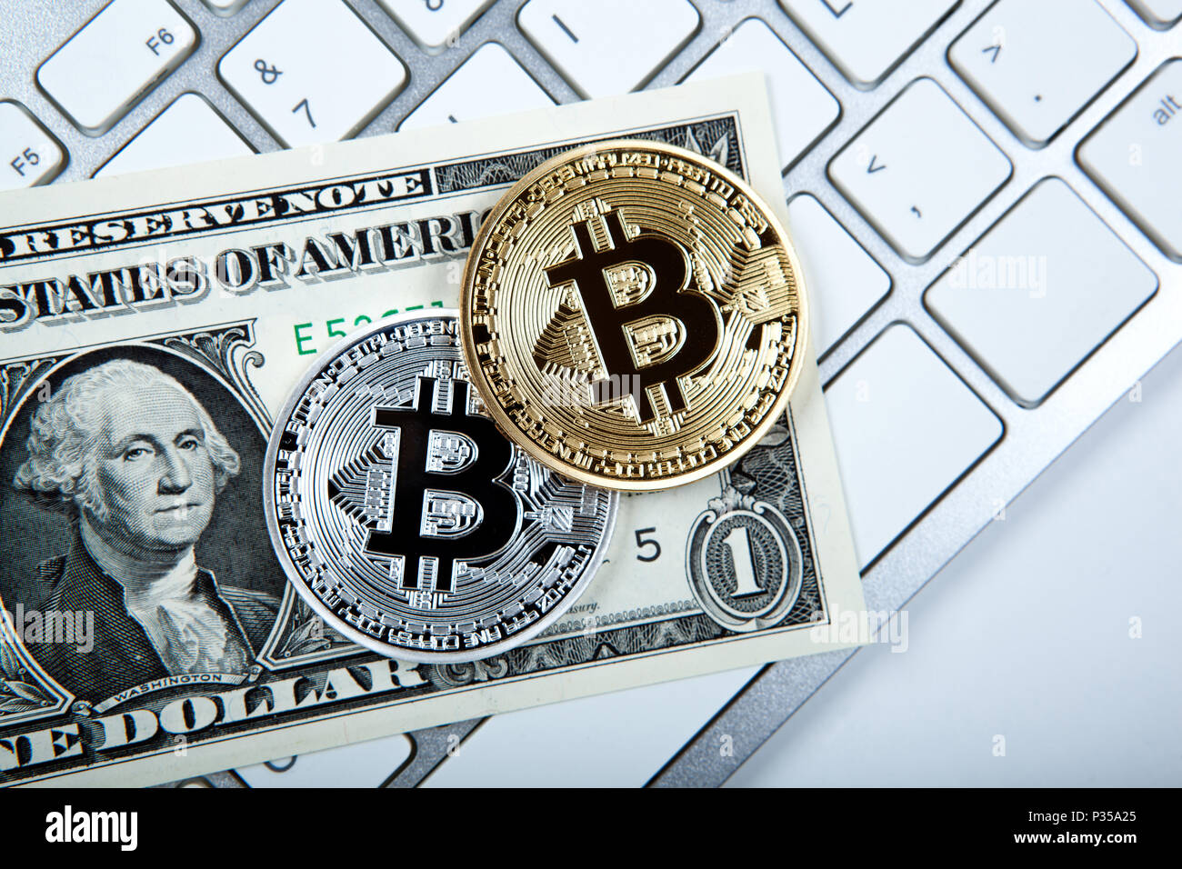 two coins of bitcoin and a dollar bill on the keyboard close up Stock ...