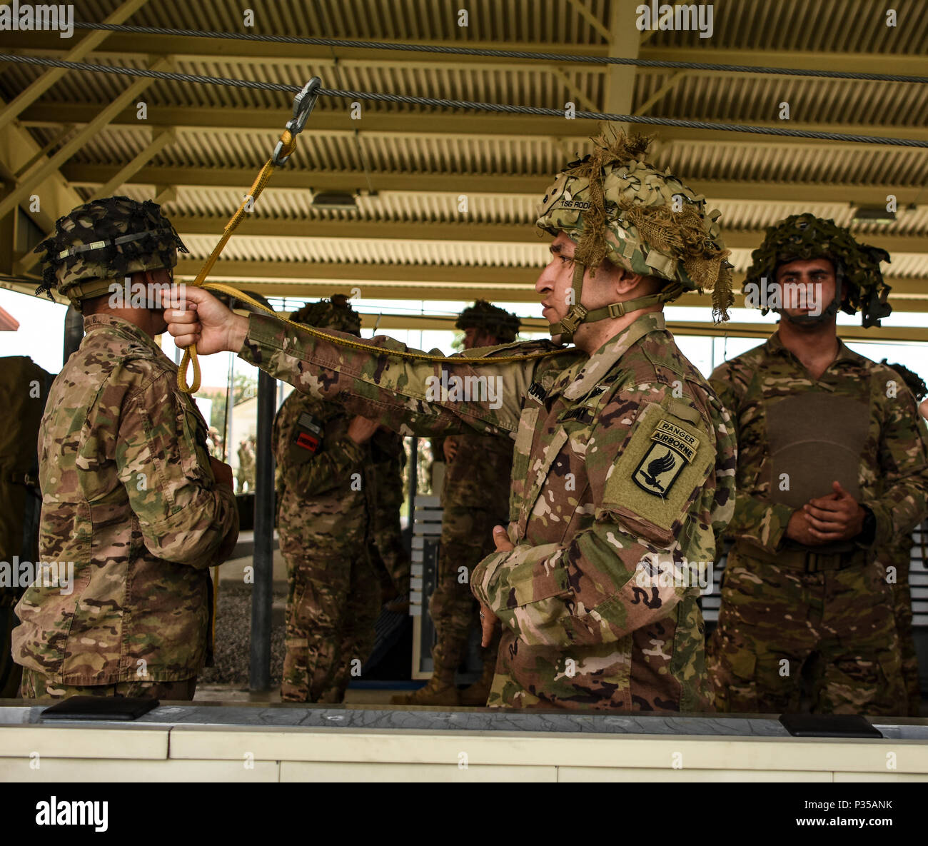 A paratrooper holds his static line out toward the jumpmaster as he ...