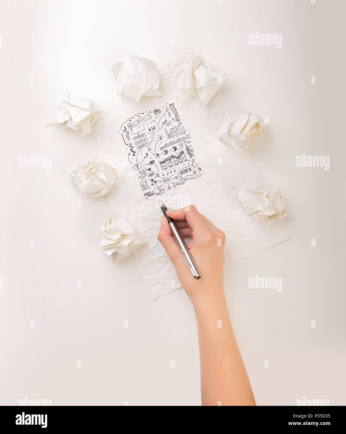Female hand next to a few crumpled paper balls drawing charts and ...