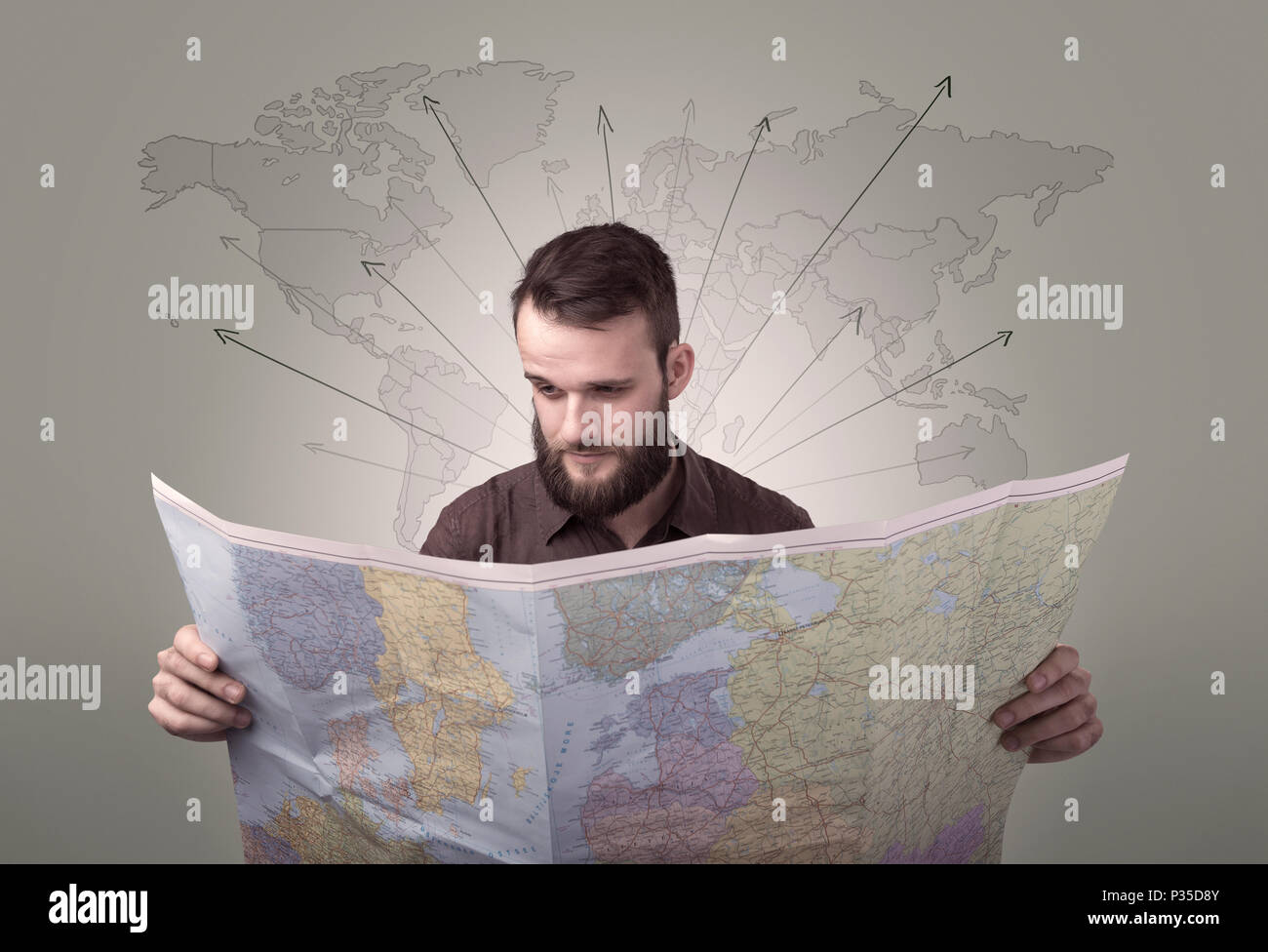 Handsome young man holding a map with world map and arrows behind him ...