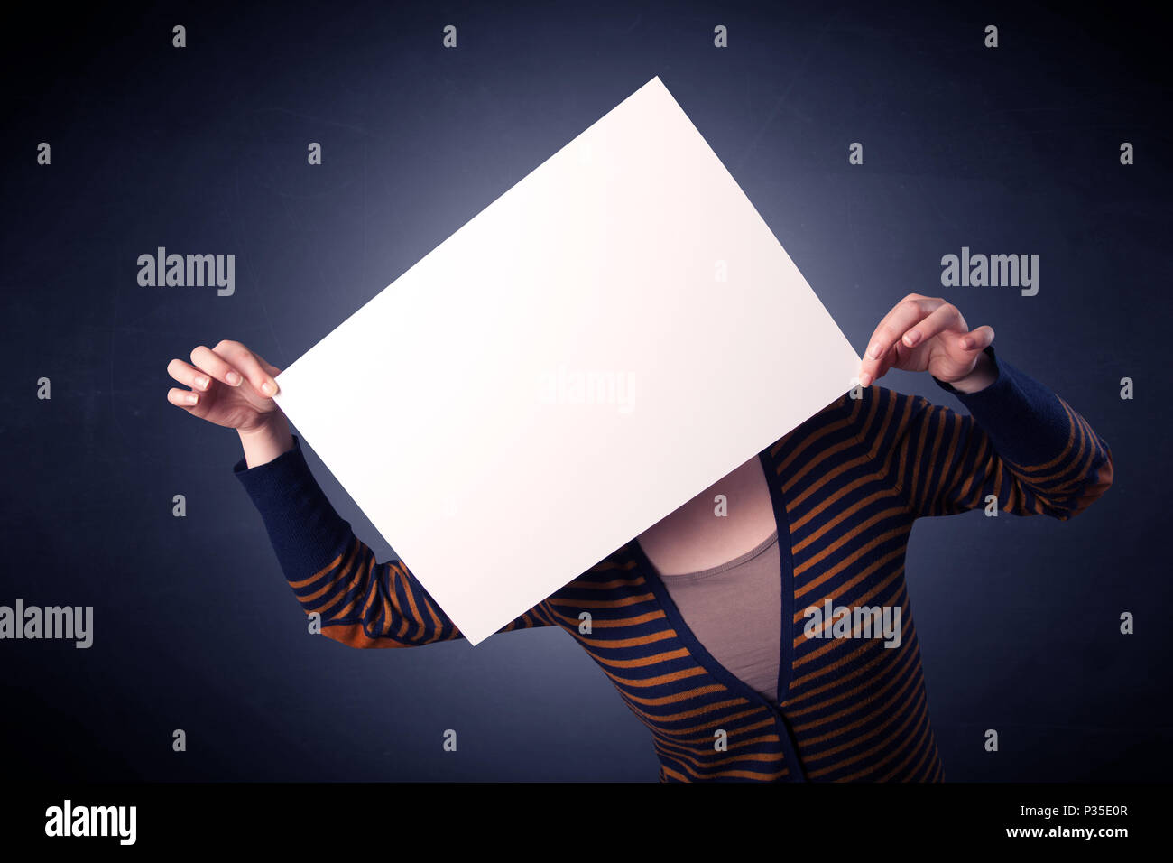 Young casual woman hiding behind a blank piece of paper Stock Photo - Alamy