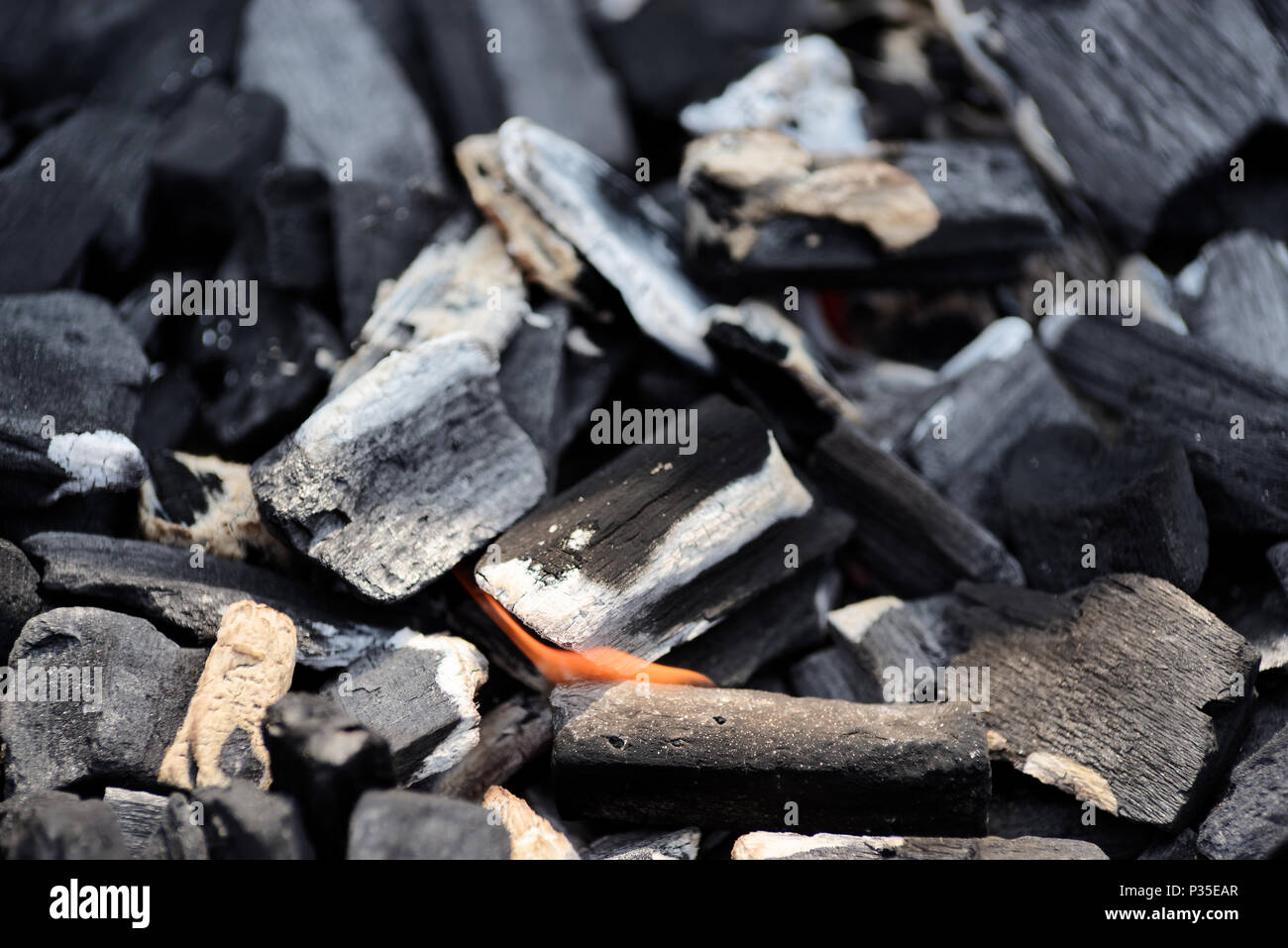 Close-up top view of hot charcoal glowing in a grill pit. Abstract ...