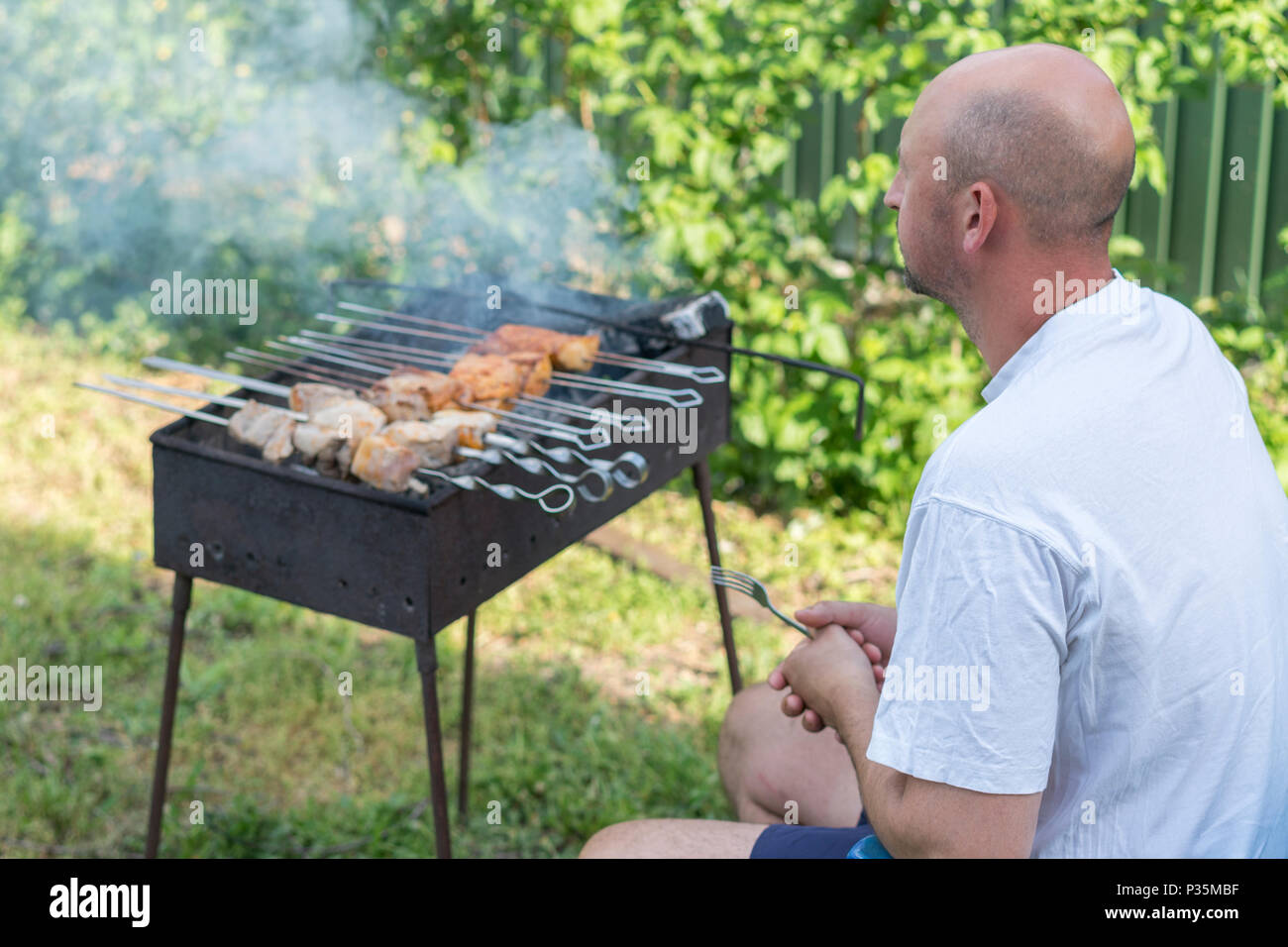 Man cooking meat on barbecue. Young couple making barbecue in their ...