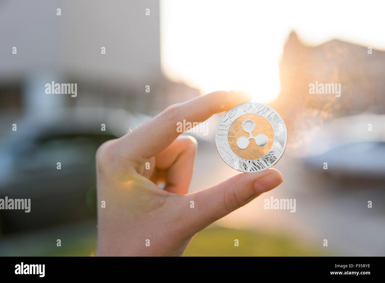 Golden silver Ripple coin in hand on a blurred sunset background. Hand ...