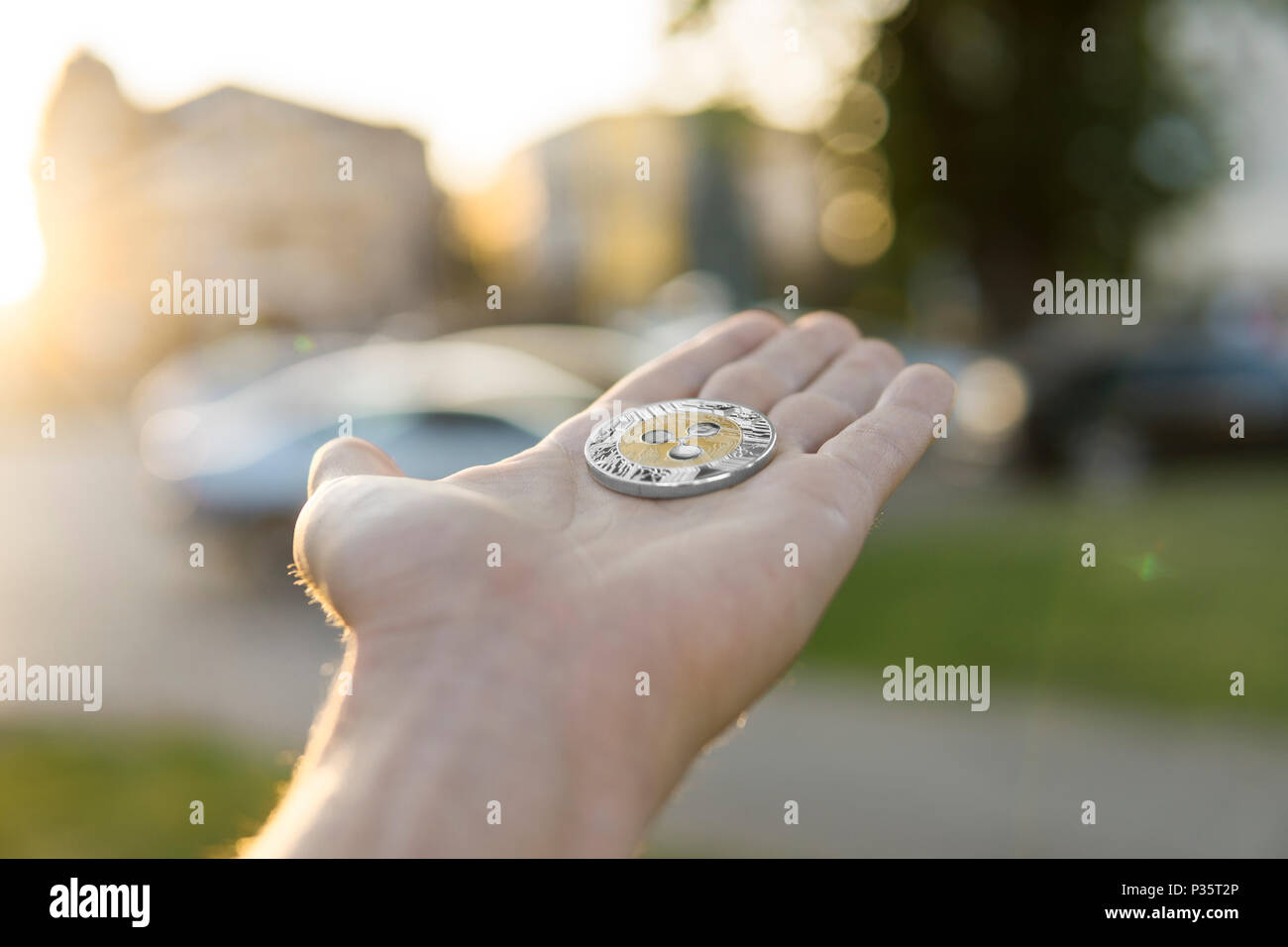 Golden silver Ripple coin in hand on a blurred sunset background. Hand ...
