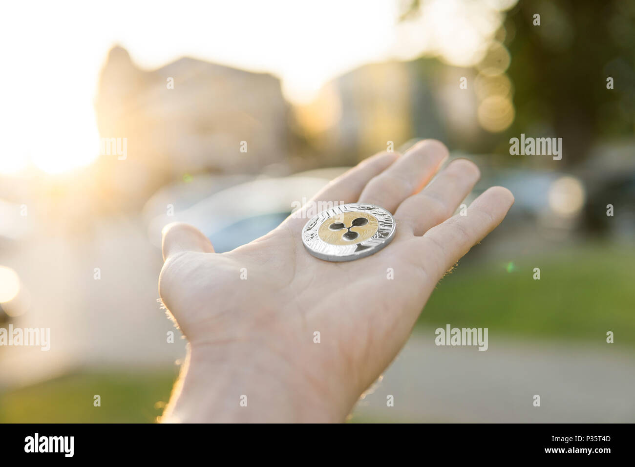 Golden silver Ripple coin in hand on a blurred sunset background. Hand ...