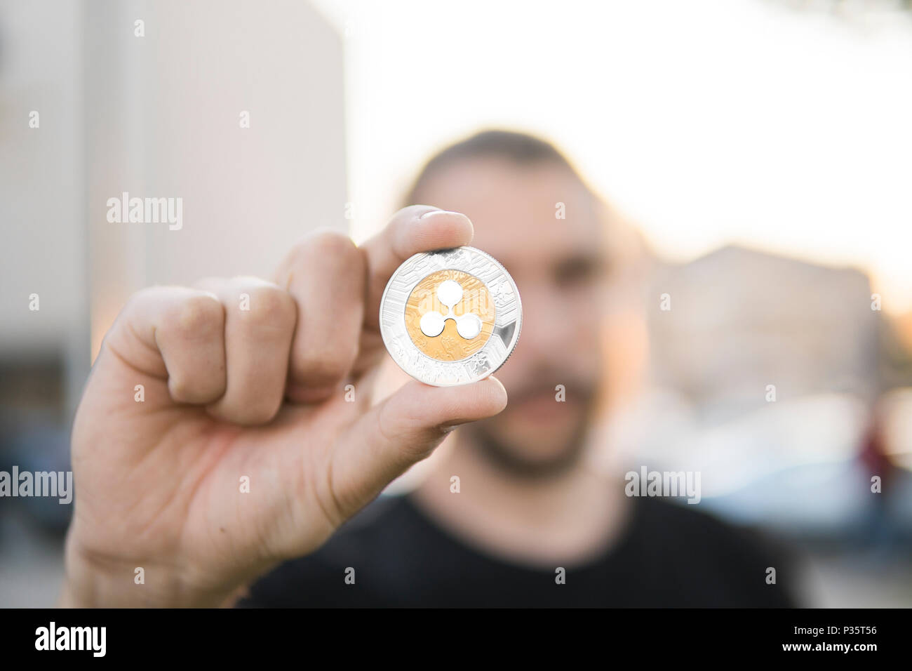 Golden silver Ripple coin in hand on a blurred sunset background with a ...
