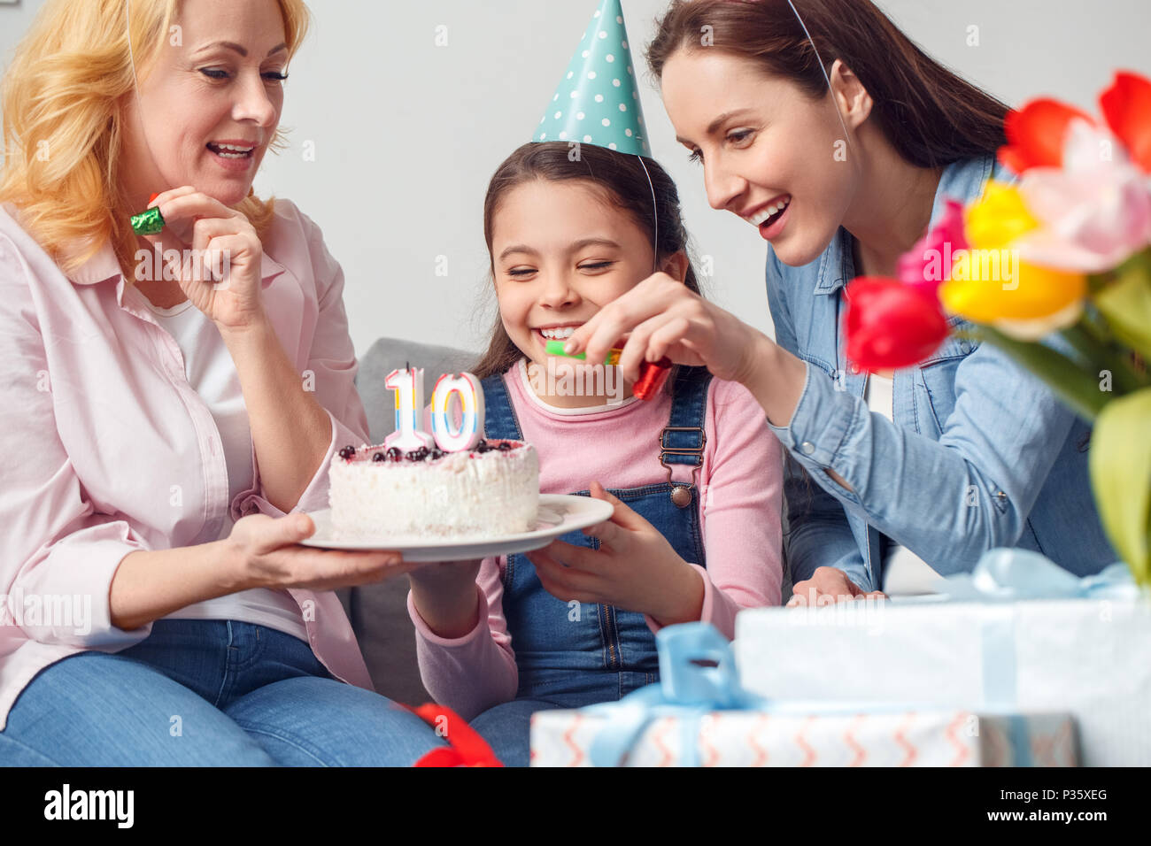 Two women and girl together at home celebrating birthday sitting on ...