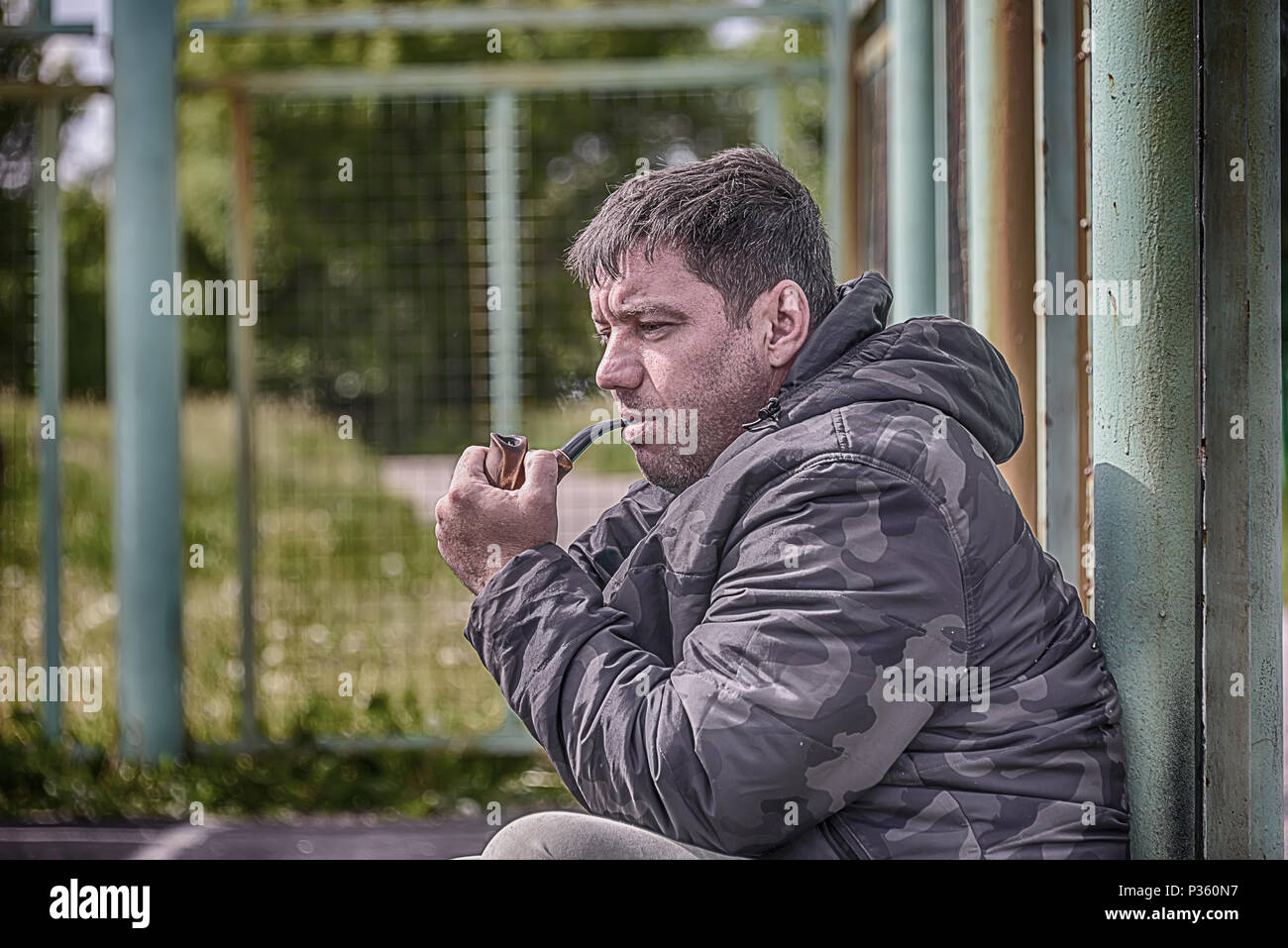 the man is smoking a pipe, close-up, in the cool windy weather, the ...