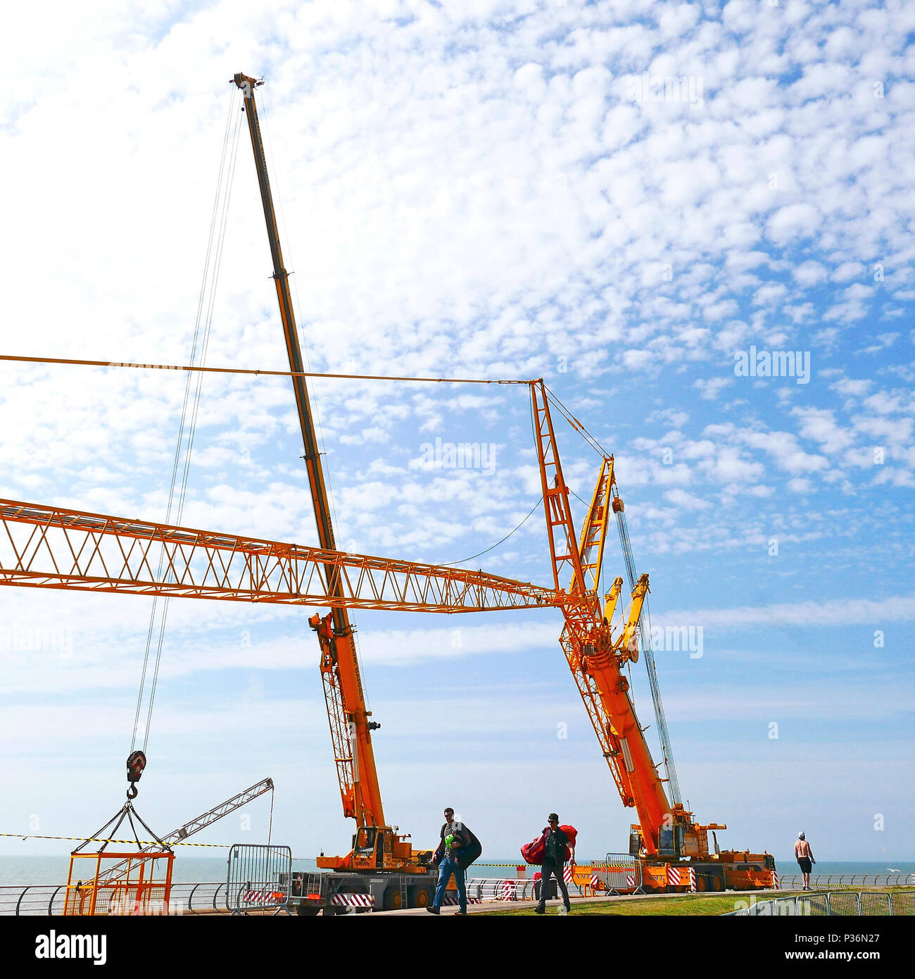 Two competitors walk beneath the giant crane being prepared for the UK ...