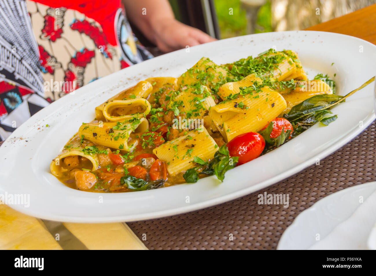 Plate of fish macaroni with tomatoes and basil in a restaurant on the ...