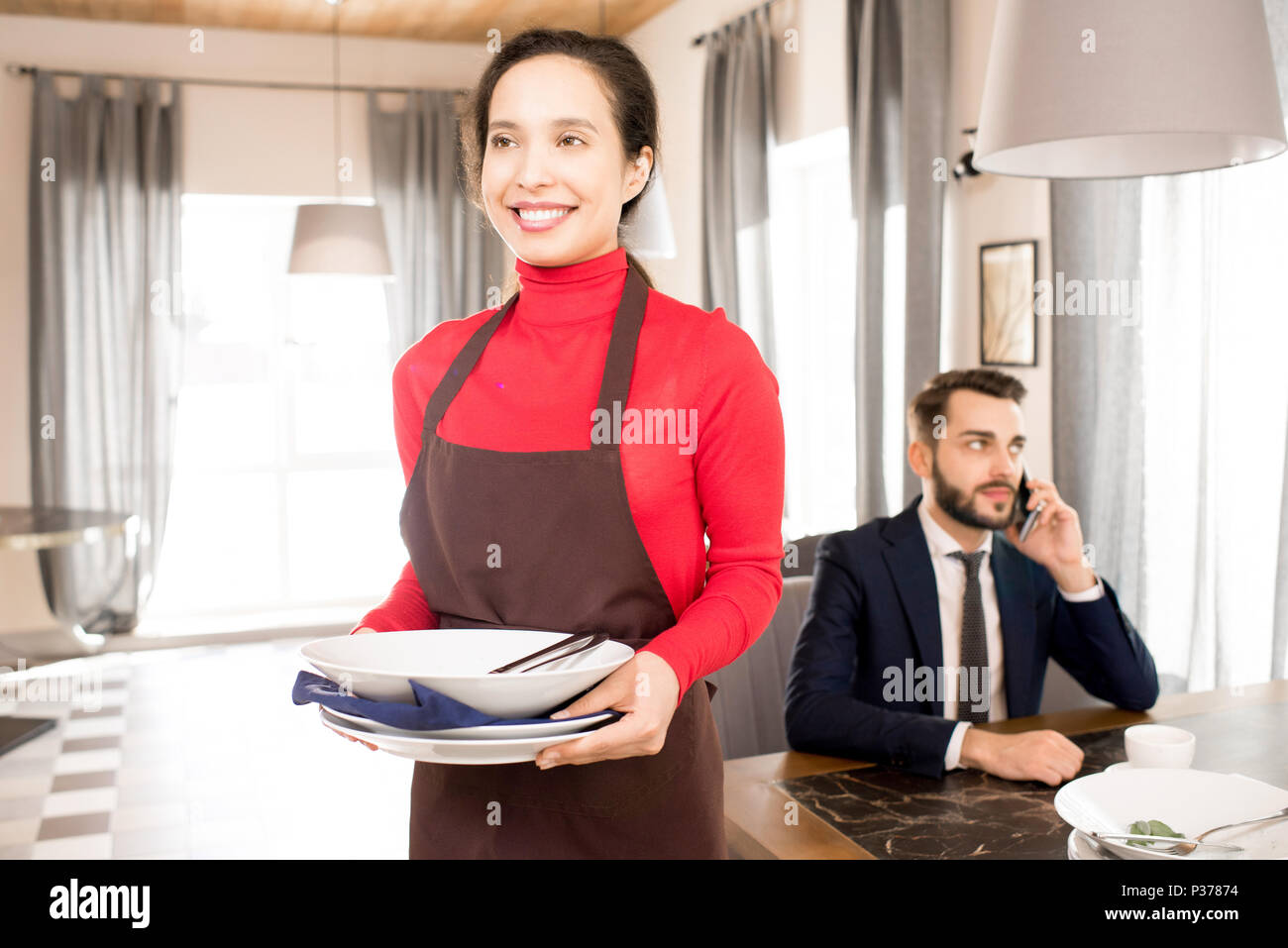 Positive waitress carrying dirty dishes away Stock Photo - Alamy