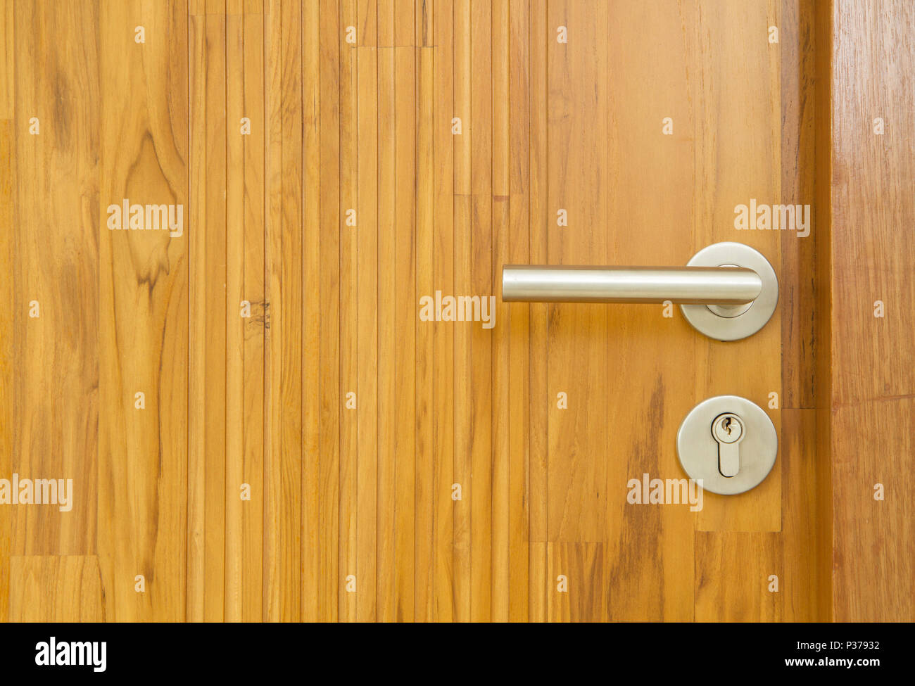 Modern style door handle on wooden door Stock Photo - Alamy
