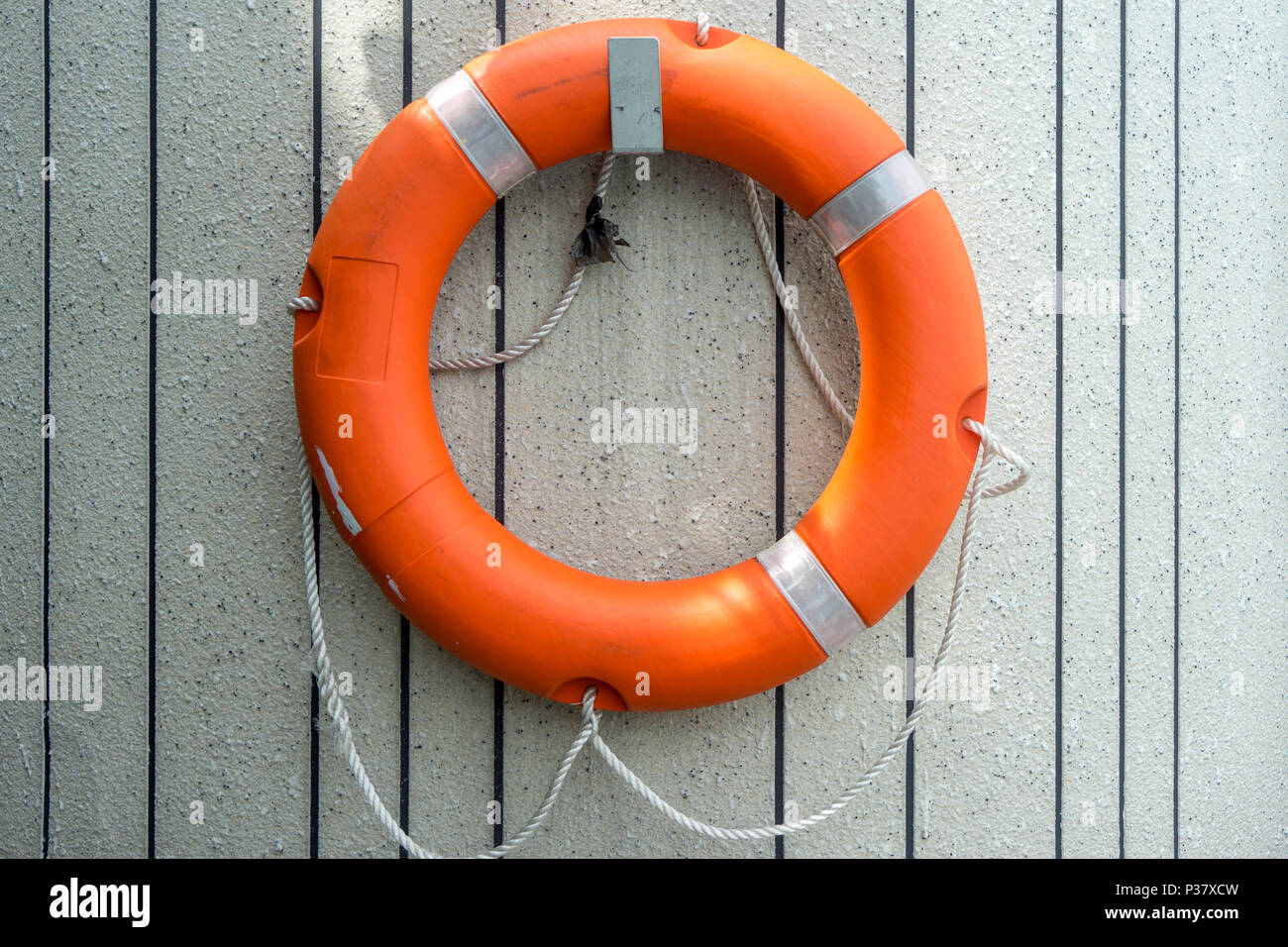 Orange Lifebuoy hanging on stone cement wall, Water rescue emergency ...