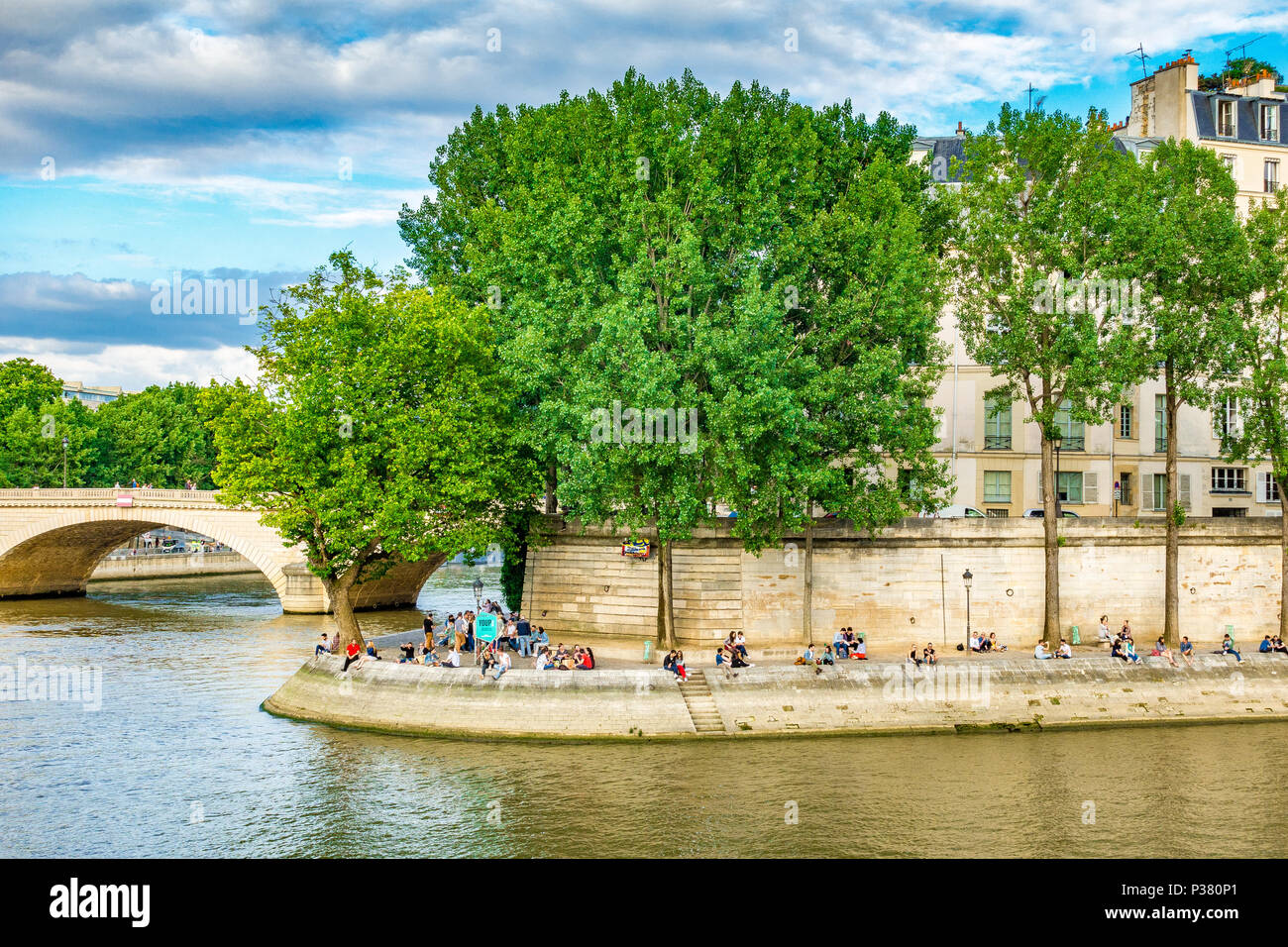 People hang out on the tip of the Île Saint-Louis at Place Louis Aragon ...
