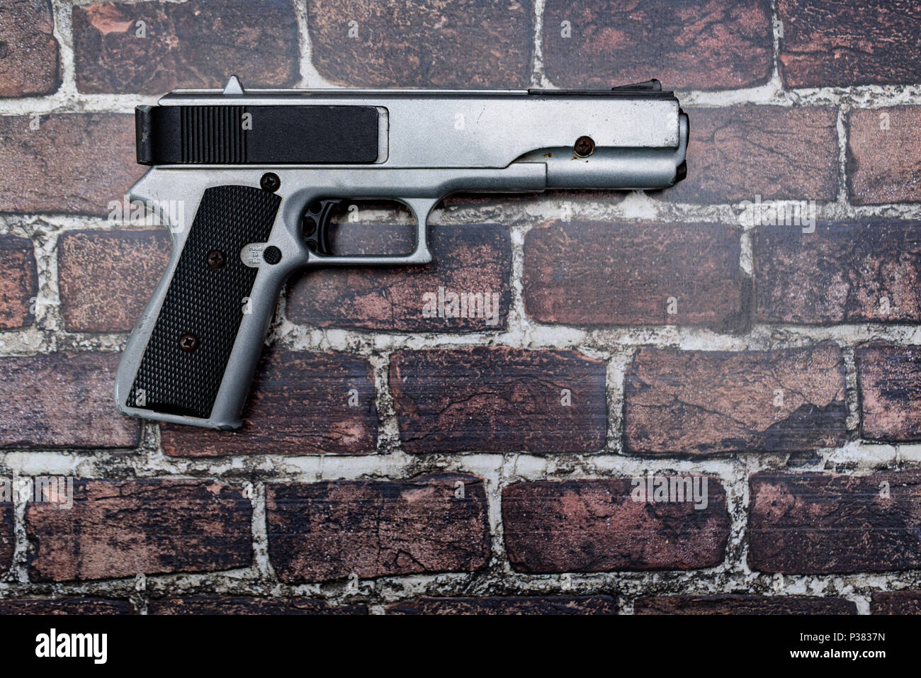 Black & Silver Hand Gun isolated on a brick background Stock Photo - Alamy