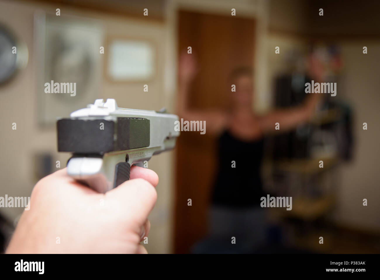 Woman held at gunpoint in her home by a burglar or intruder Stock Photo ...