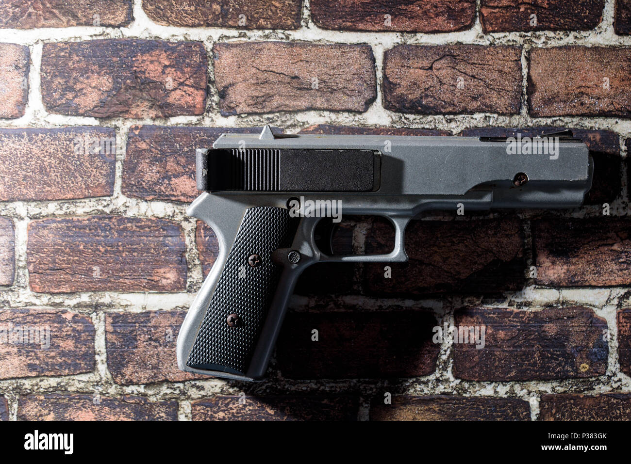 Black & Silver Hand Gun isolated on a brick background Stock Photo - Alamy