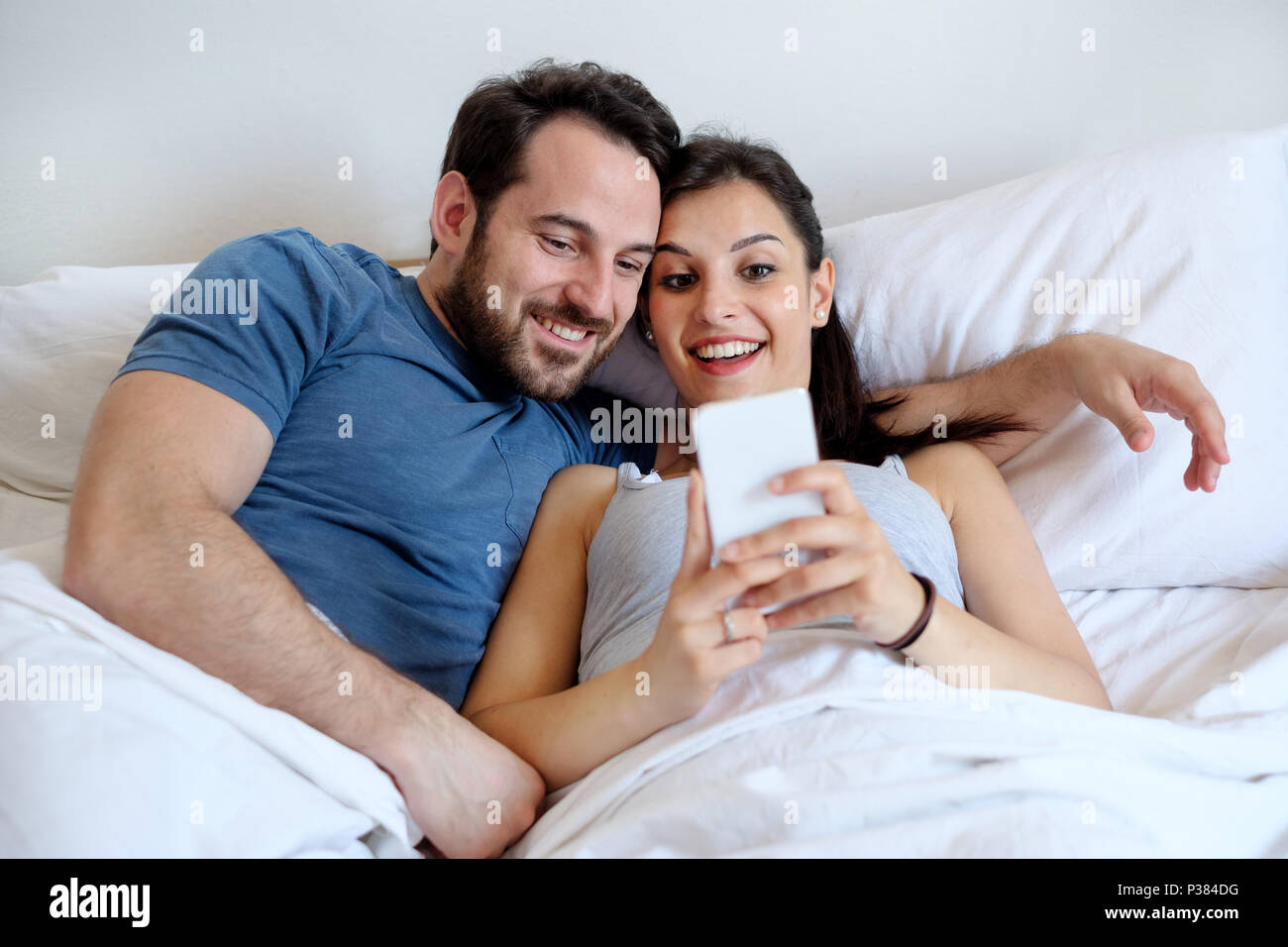 Couple smartphone bed hi-res stock photography and images - Alamy