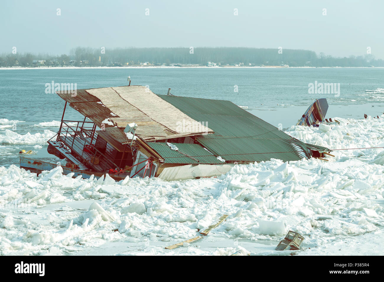 Crashed raft house and fishing boat in frozen river. Winter time, river ...