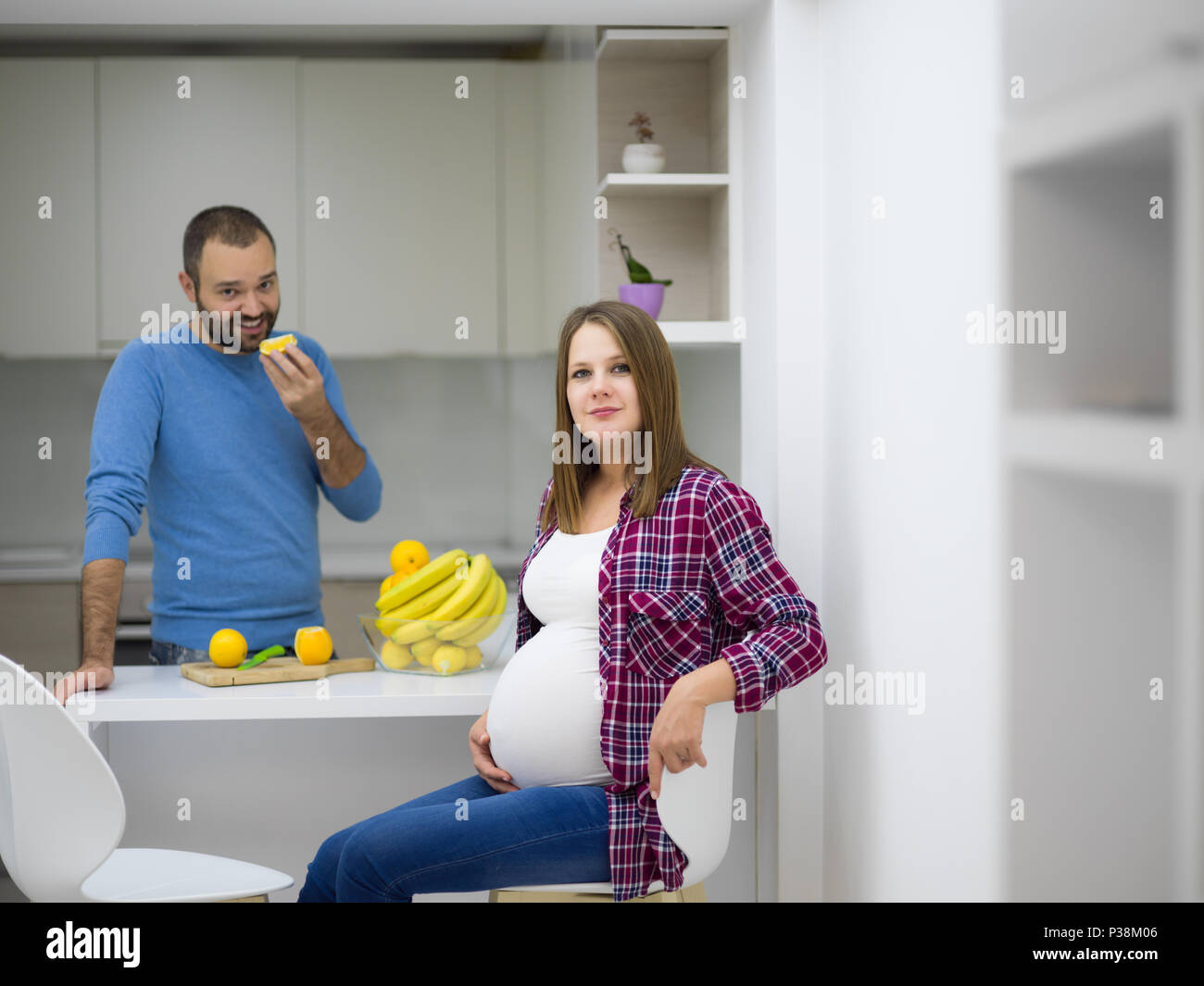 young pregnant couple cooking food fruit lemon juice at kitchen ...