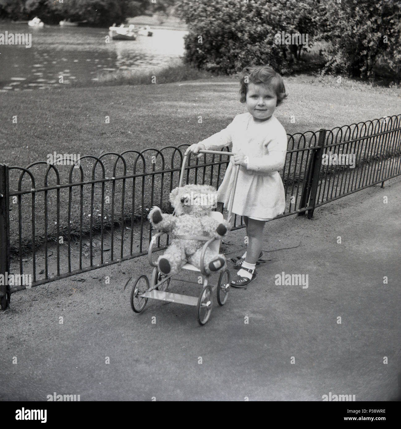 1950s, historical, young girl outdoors in a park wih her teddy bear ...