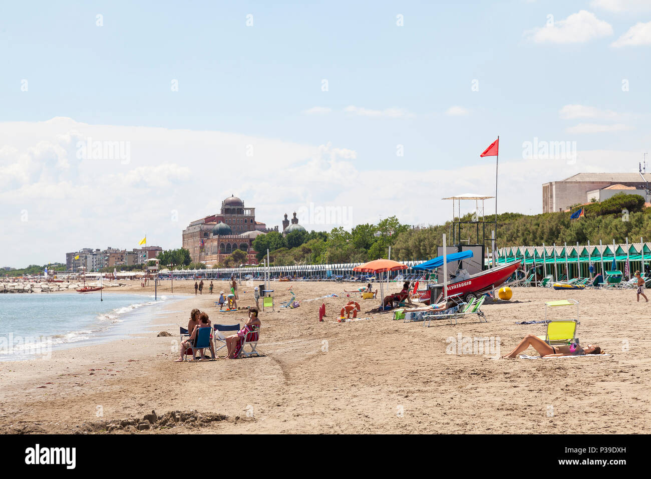 Lifeguard and sunbathers on beach with cabanas or beach huts, Lido di ...