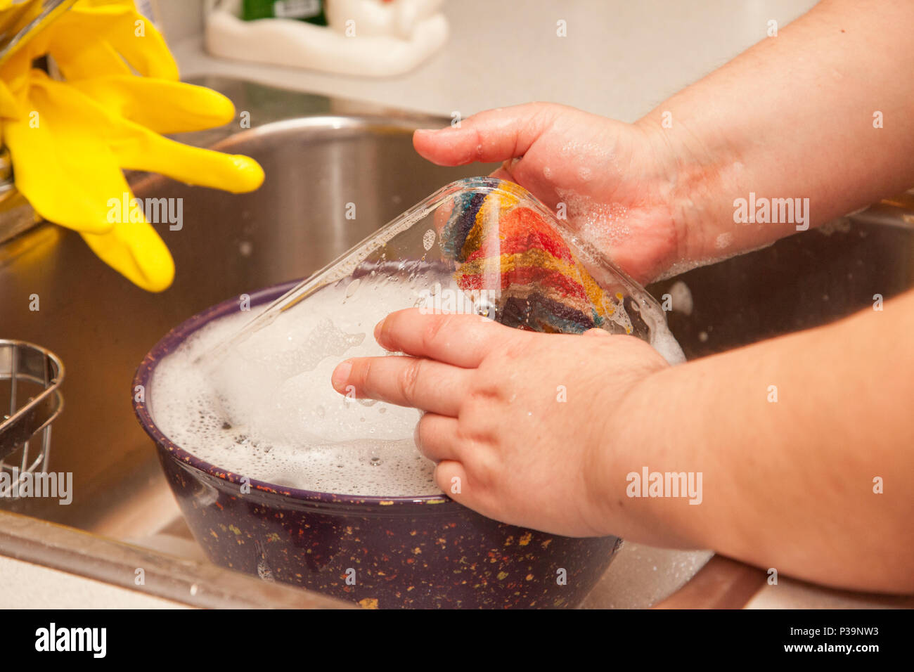 Close view of hands and a dishrag washing a bowl and glass dish in the ...