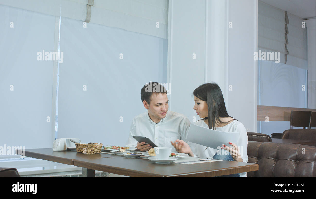 Two colleagues discussing work while eating lunch in a cafe Stock Photo ...