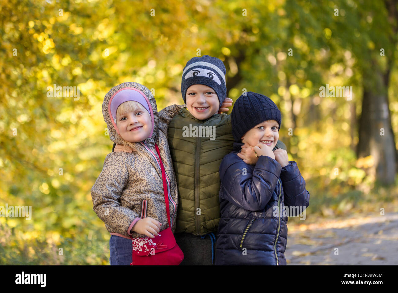 Group of happy three kids having fun outdoors in autumn park. Cute ...