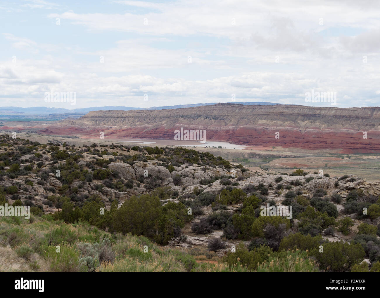 The Shoshone River in a valley with red and tan mountains as it ...
