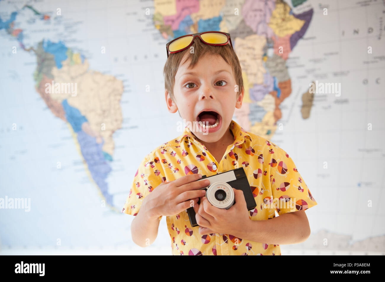 funny shouting little kid in yellow shirt with vintage camera in hands ...