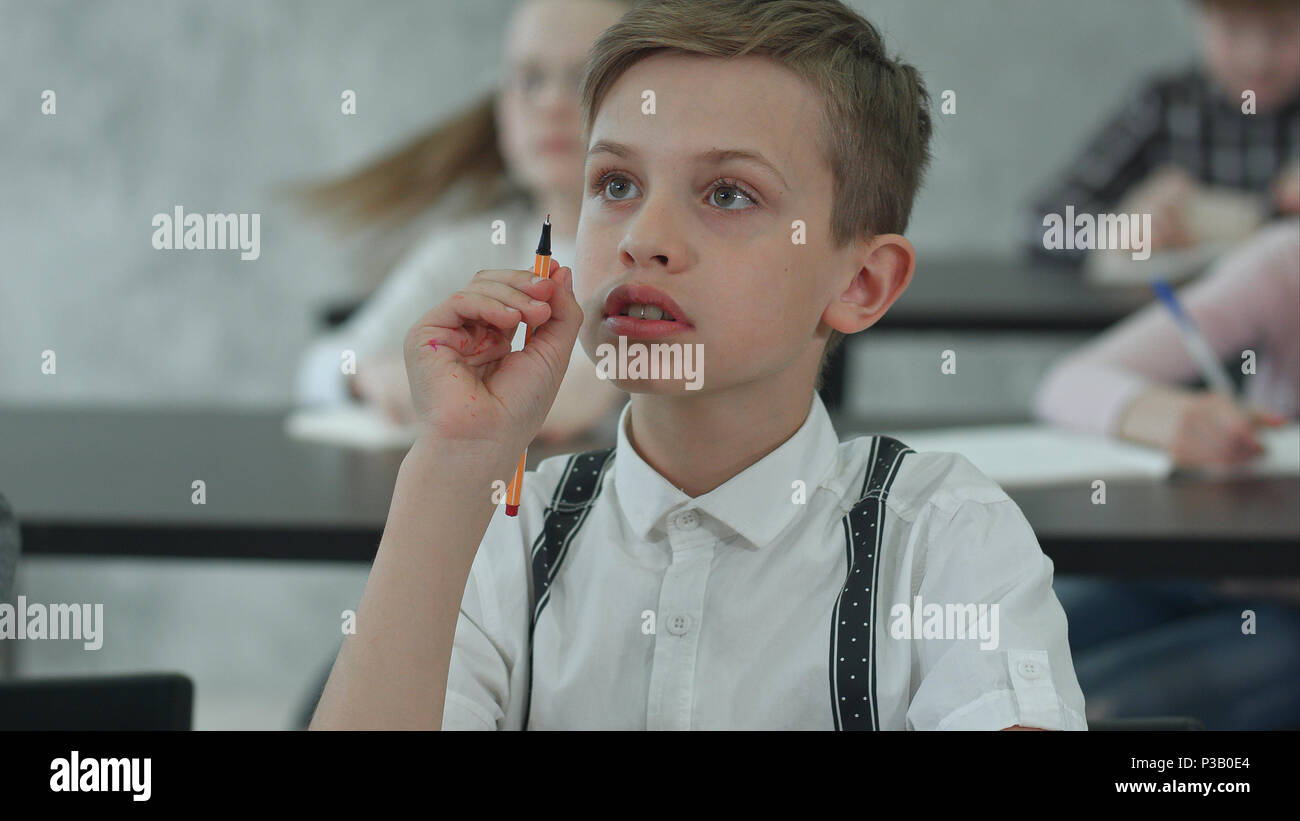 Little boy sitting at table and listening in class Stock Photo - Alamy