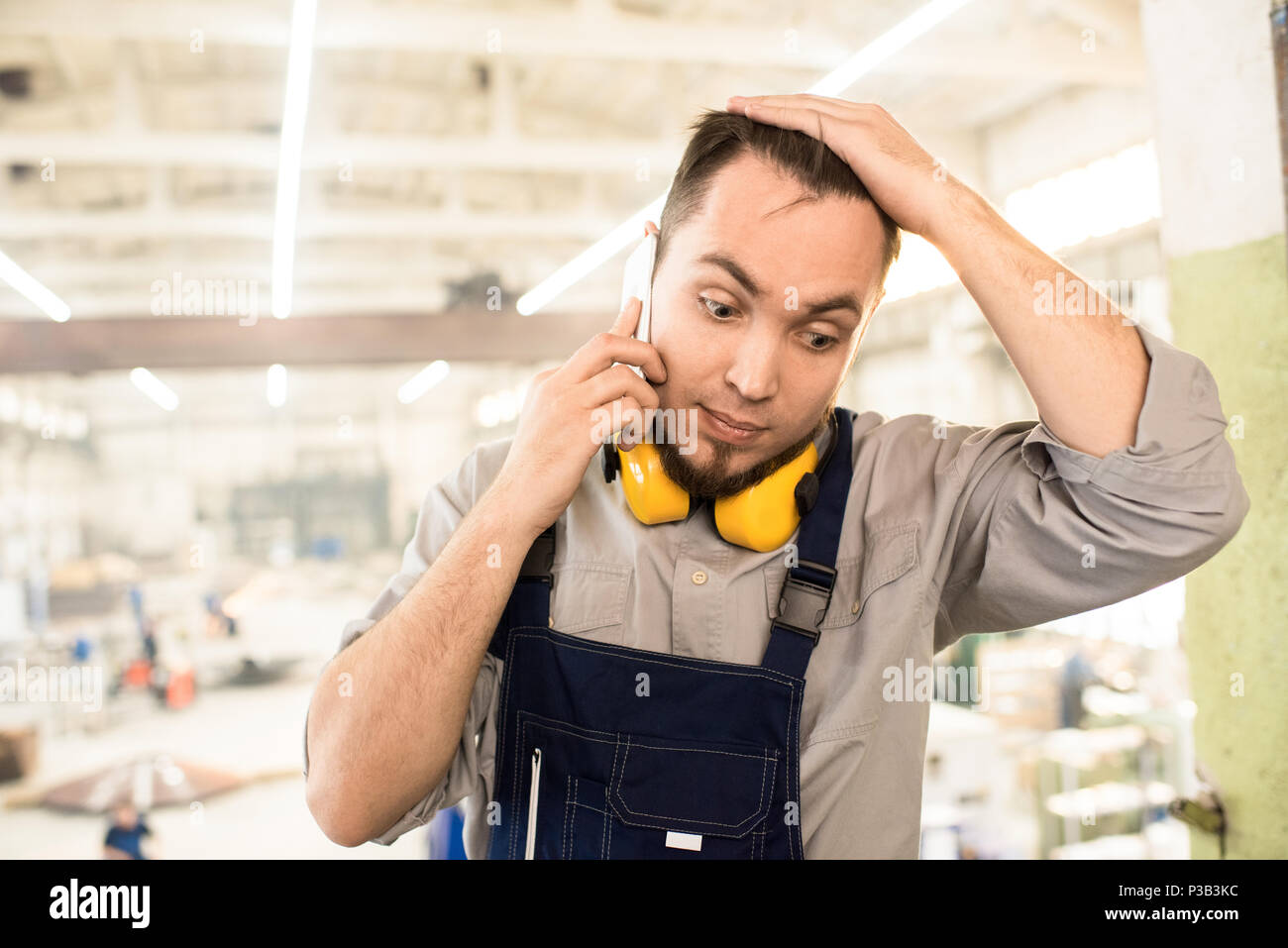 Puzzled builder calling on phone from construction site Stock Photo - Alamy