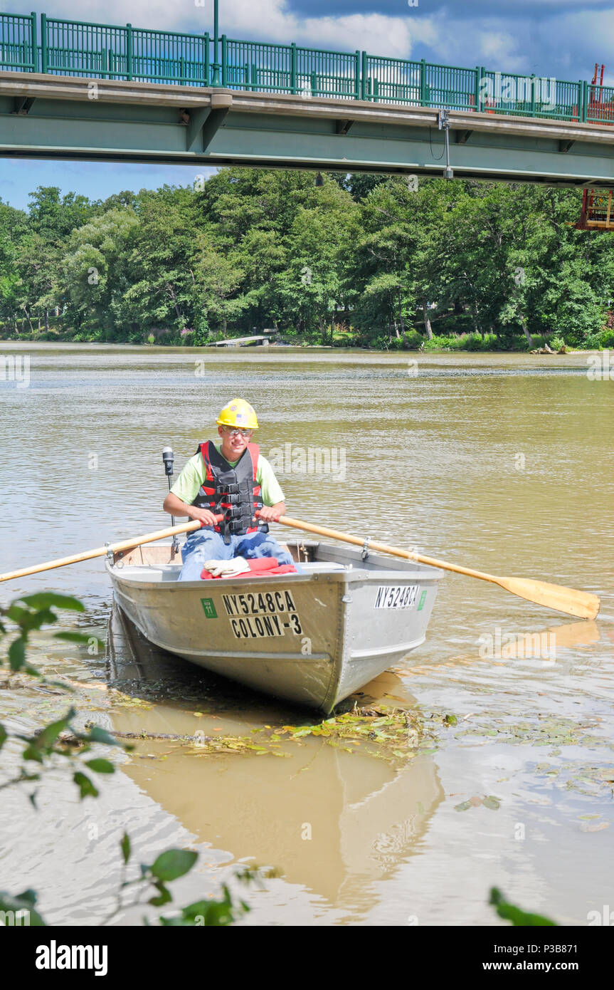 Construction worker in a rowboat spotting work being done on bridge ...
