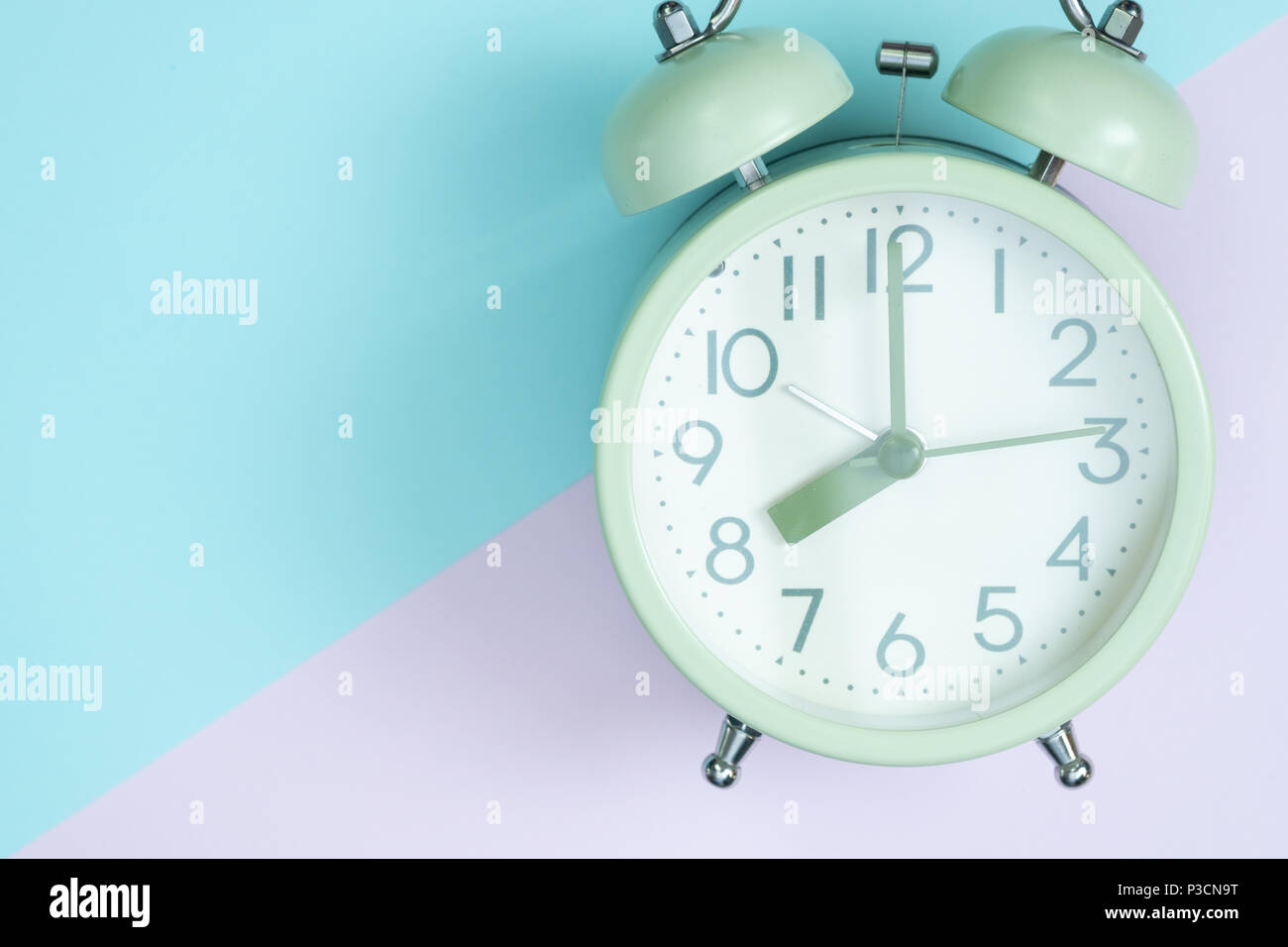 Flat lay vintage alarm clock on sweet pastel colored paper top view ...