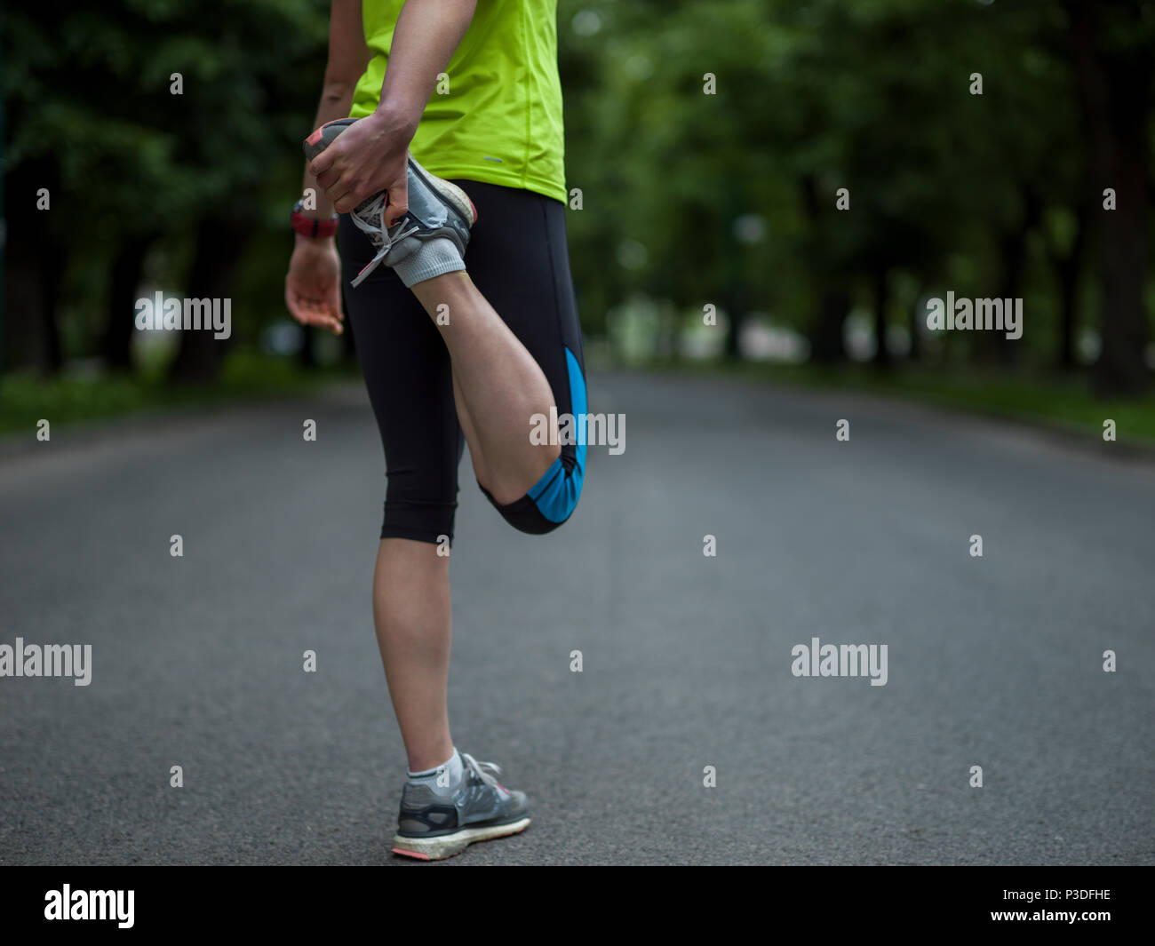 healthy female runner warming up and stretching in city park before ...