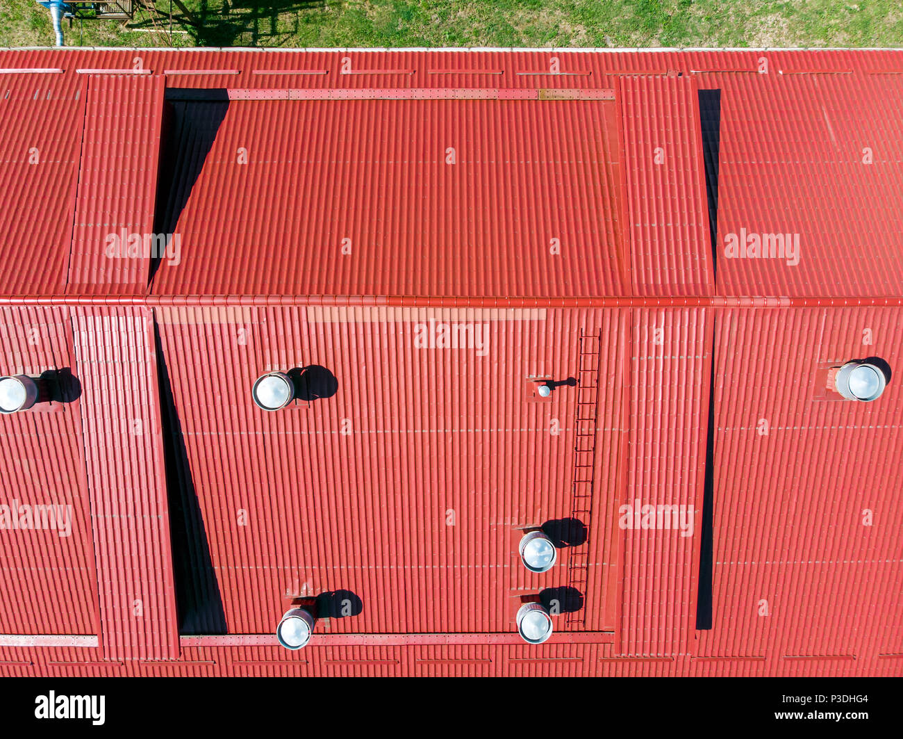aerial view of red corrugated metal factory roof with tubes of ...