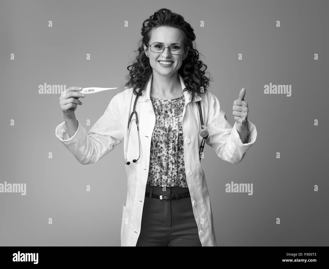 smiling pediatrist woman in white medical robe showing thumbs up and a ...