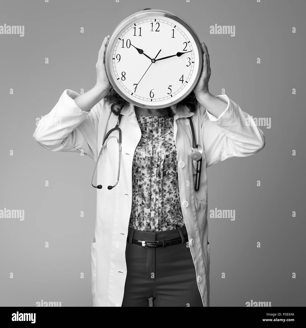 paediatrist woman in white medical robe holding clock in the front of ...