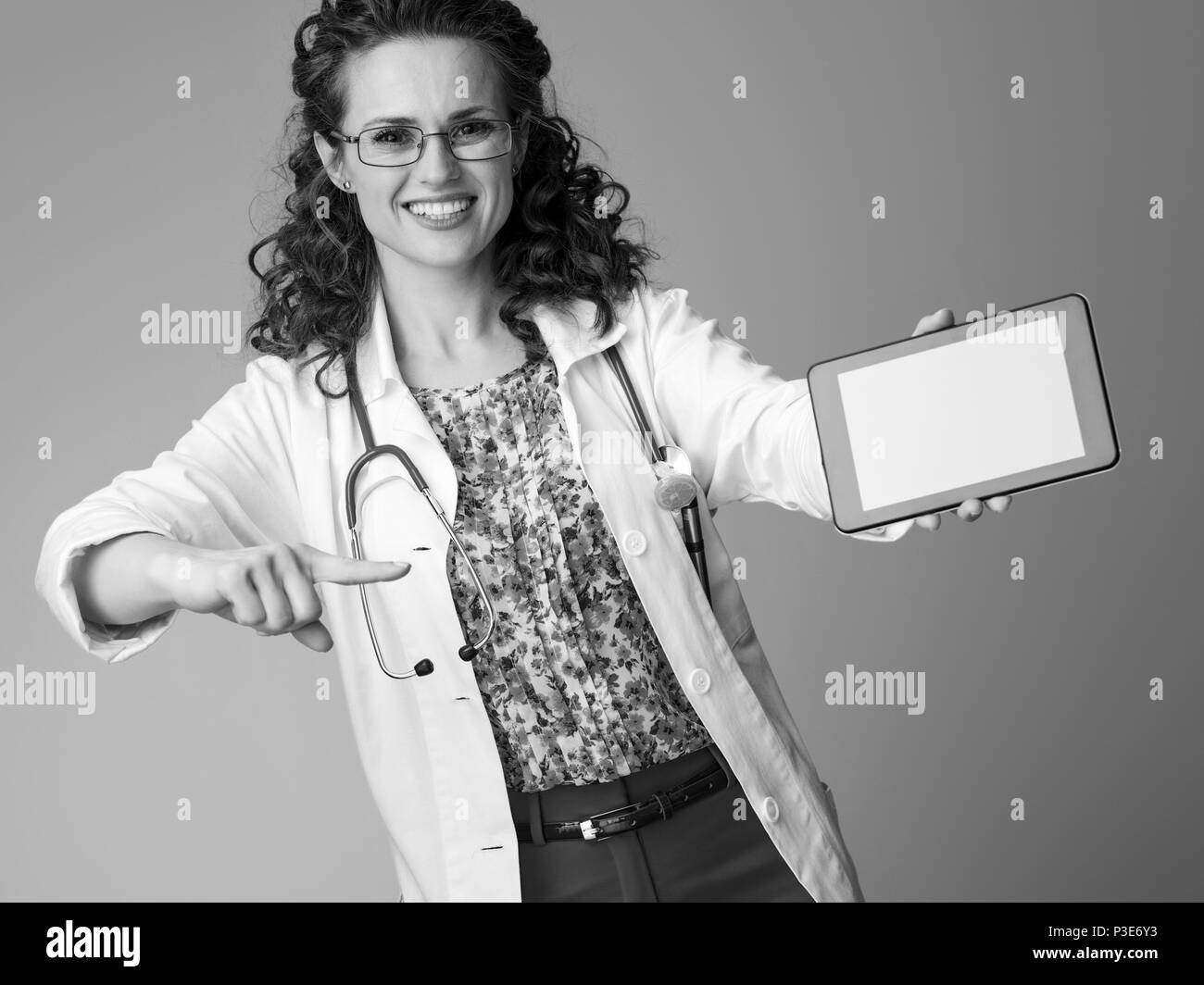 happy pediatrist doctor in white medical robe pointing at tablet PC ...