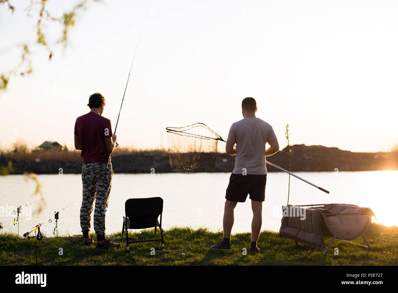 Young man fishing on a lake at sunset and enjoying hobby Stock Photo ...