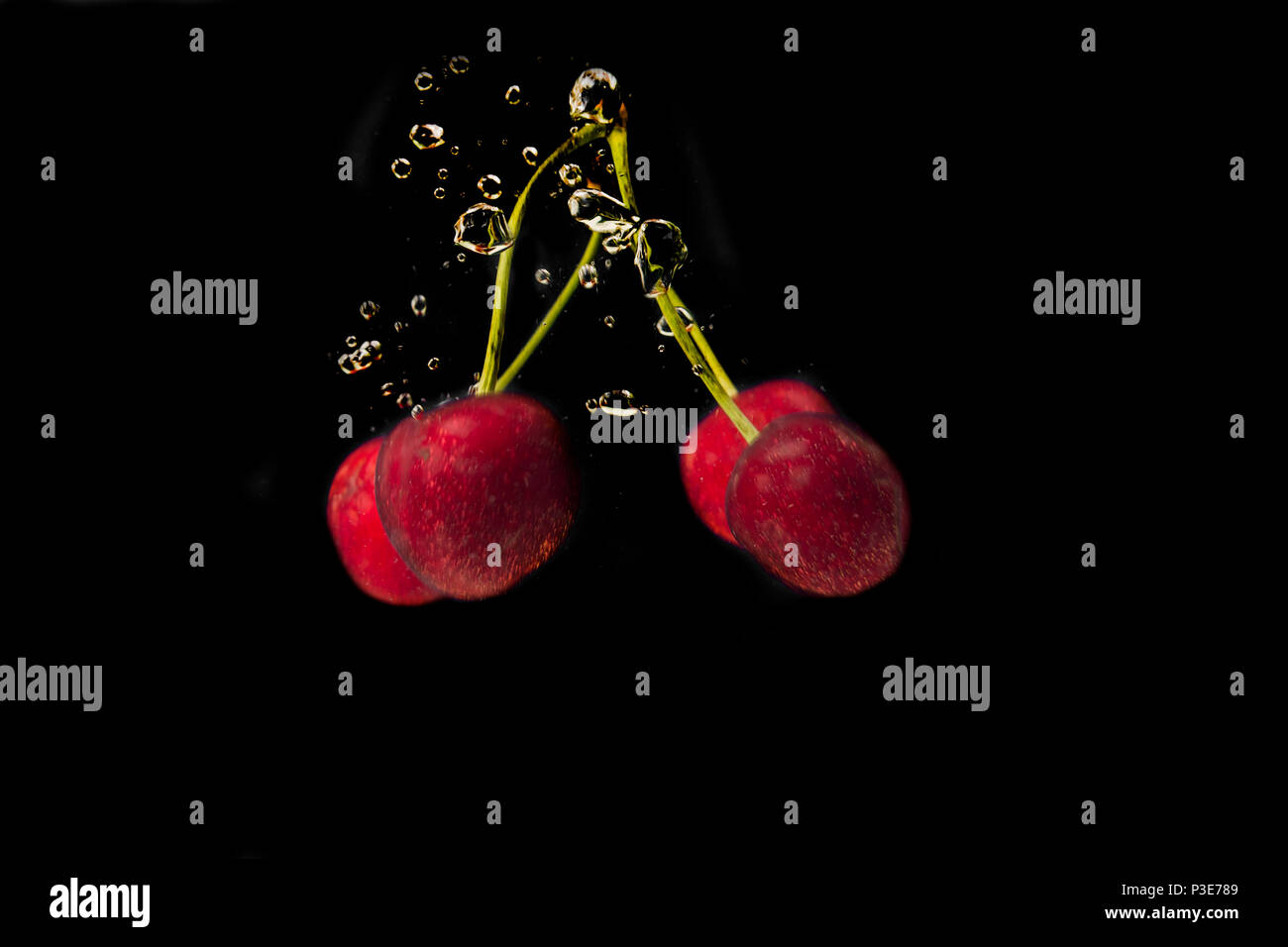 Red cherry falling into the water Stock Photo - Alamy