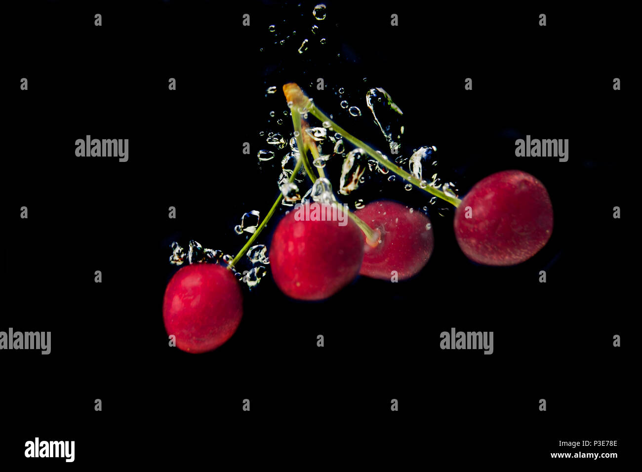 Red cherry falling into the water Stock Photo - Alamy