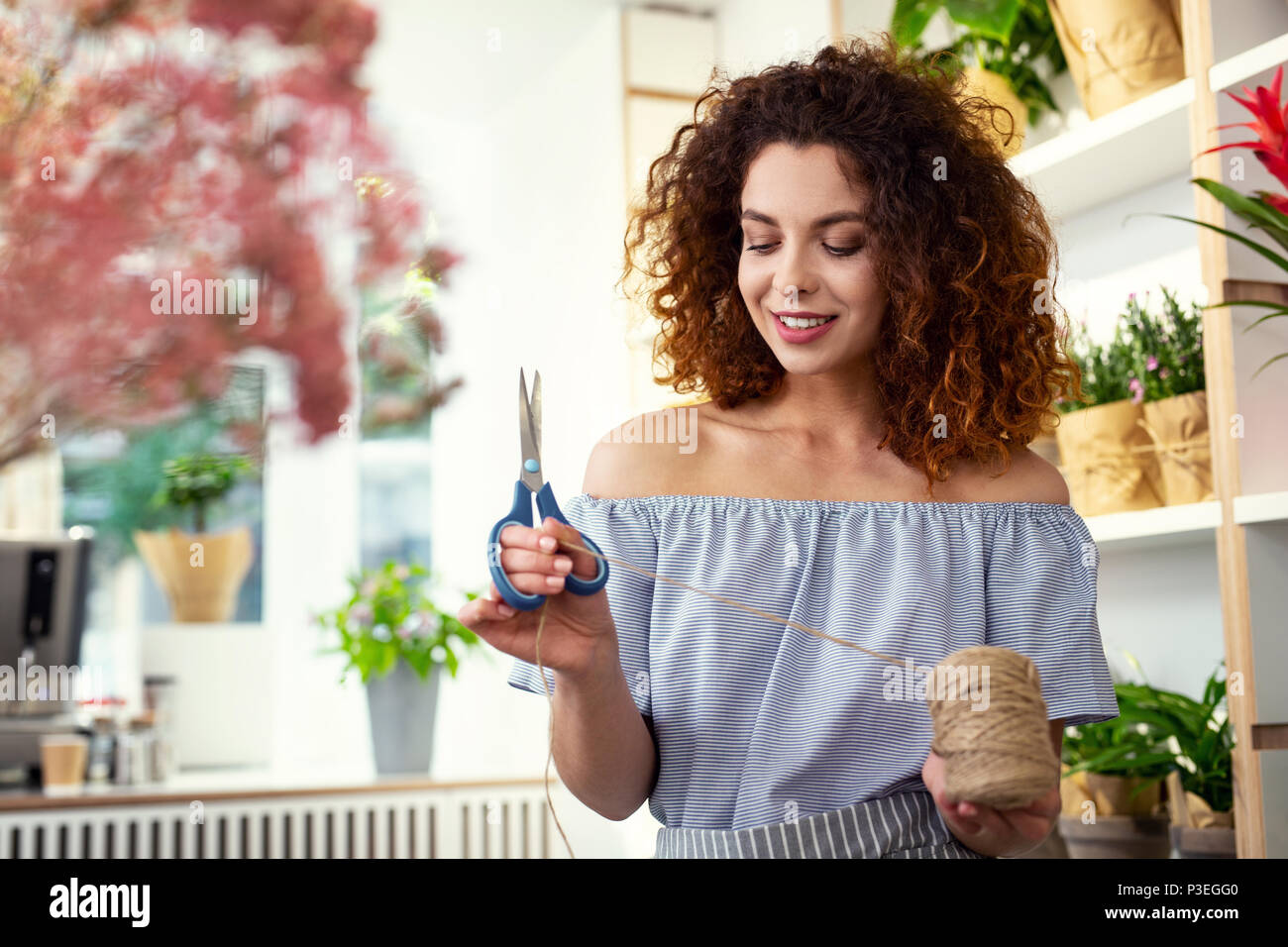 Nice pleasant woman cutting a piece of rope Stock Photo - Alamy